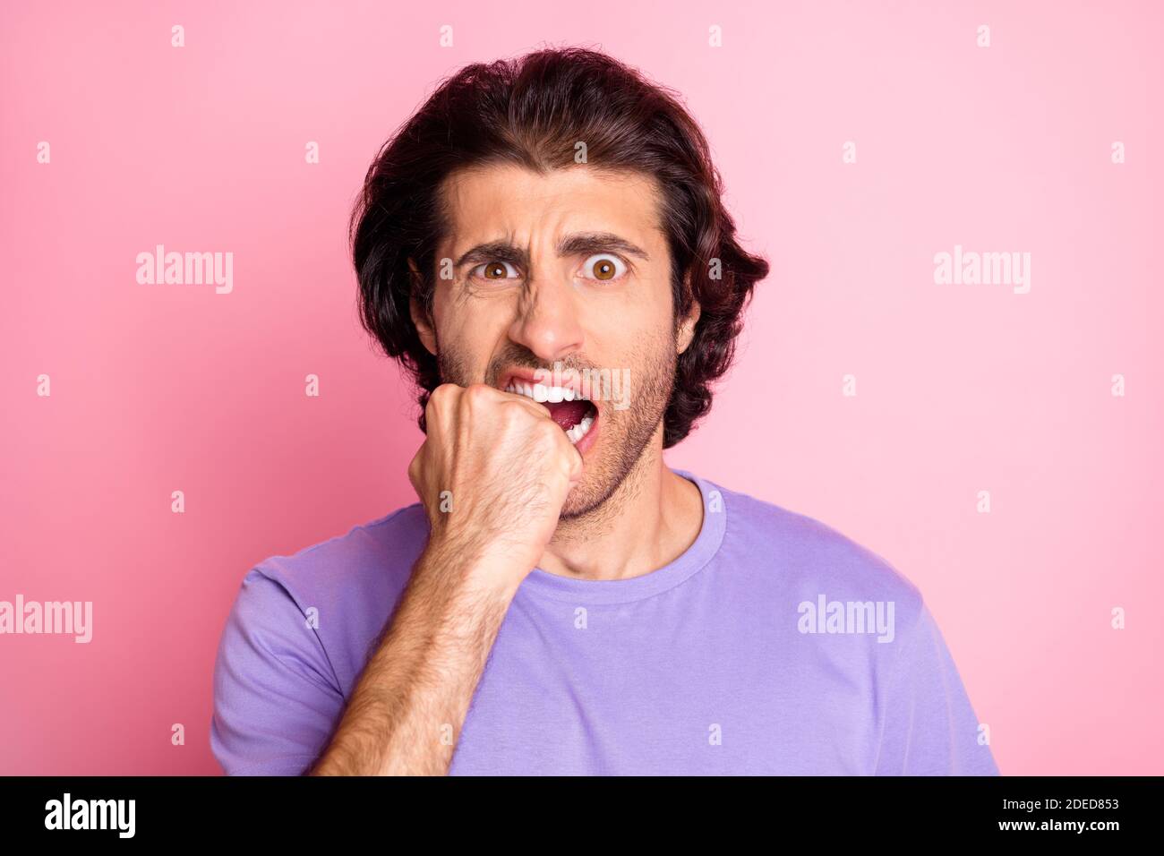 Photo of nervous young guy bite fist crazy face wear violet t-shirt ...
