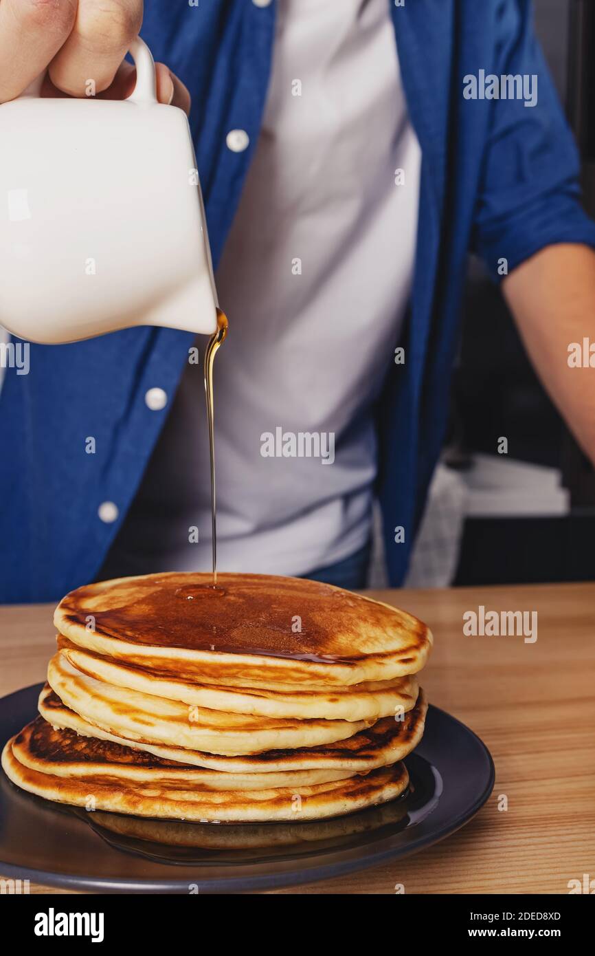 Man pouring with maple syrup on the stack of pancakes Stock Photo - Alamy