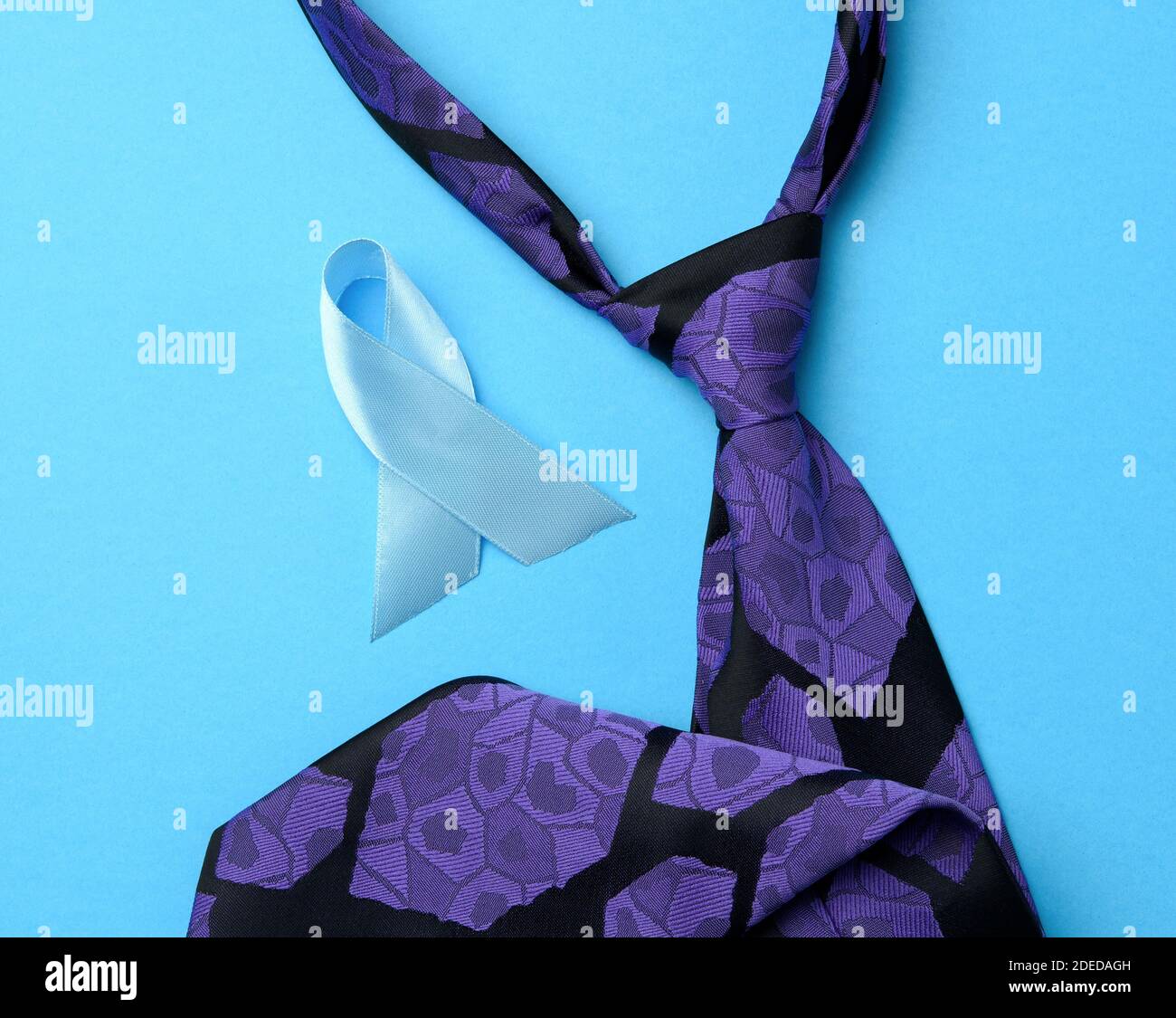 silk purple mens tie and blue ribbon folded in a loop on blue ...