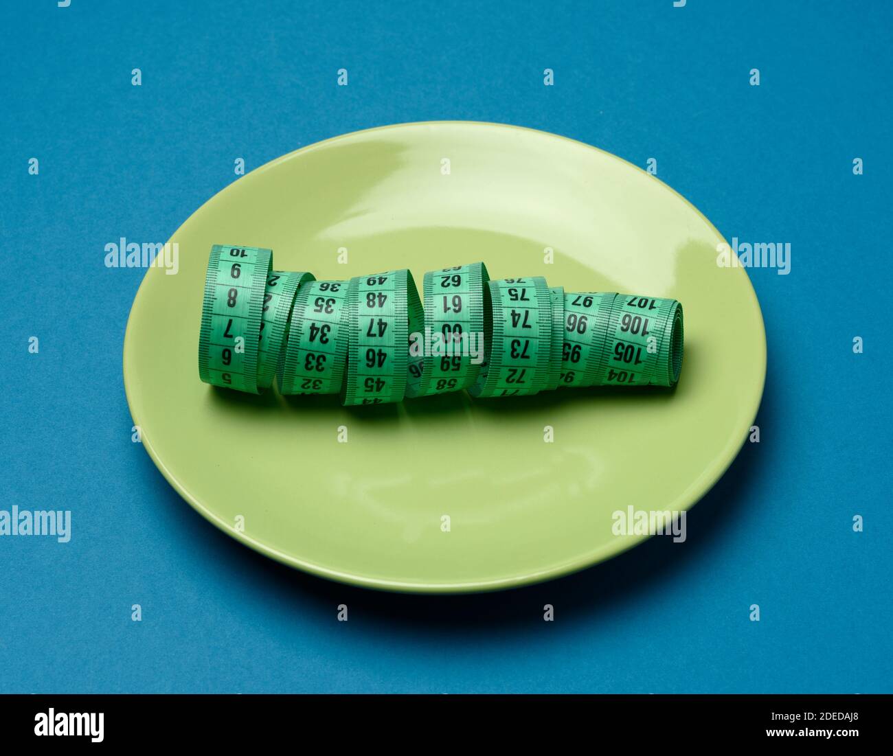 green round plate and green measuring tape on blue background, weight ...