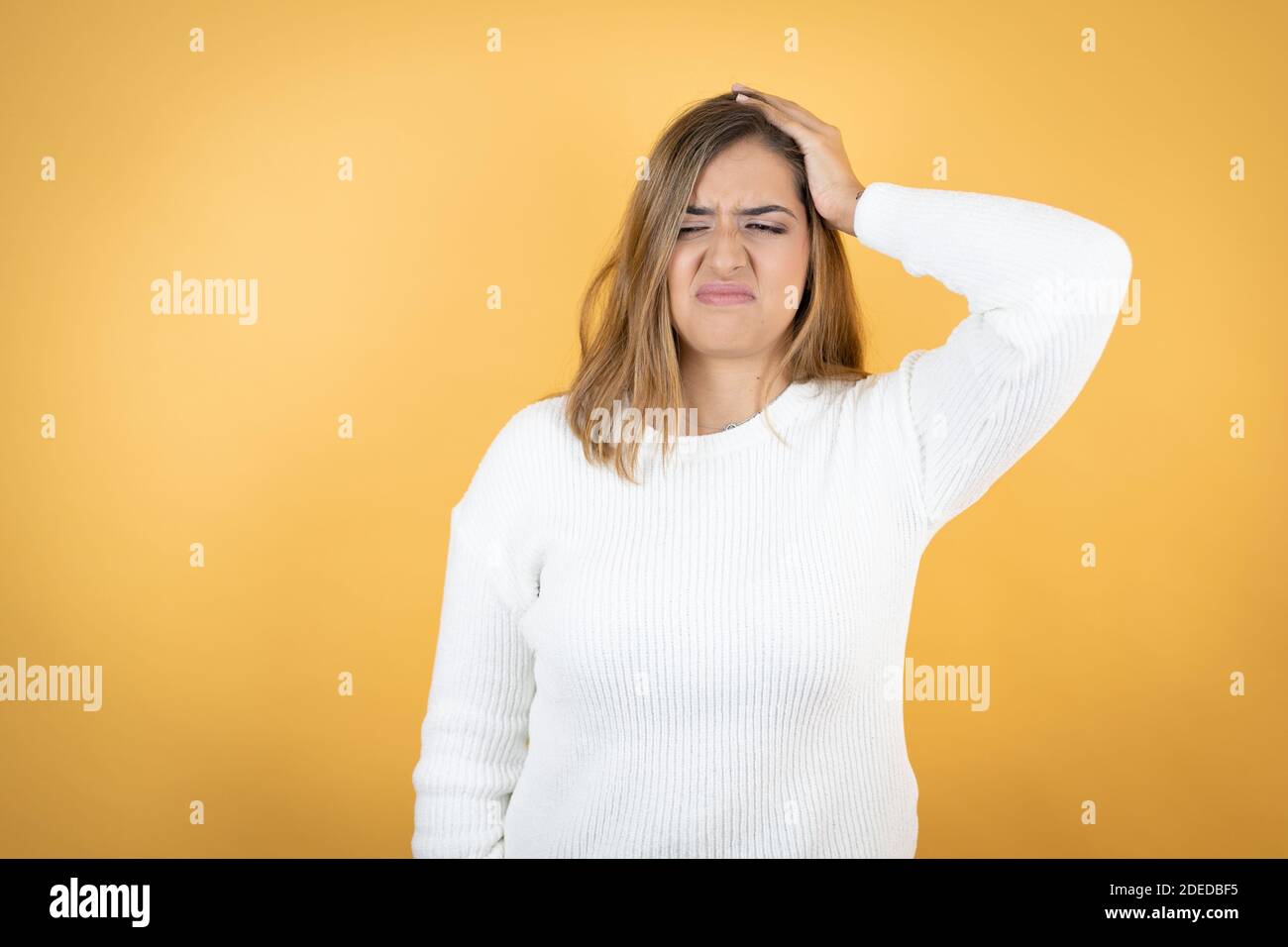 Young caucasian woman over isolated yellow background putting one hand ...