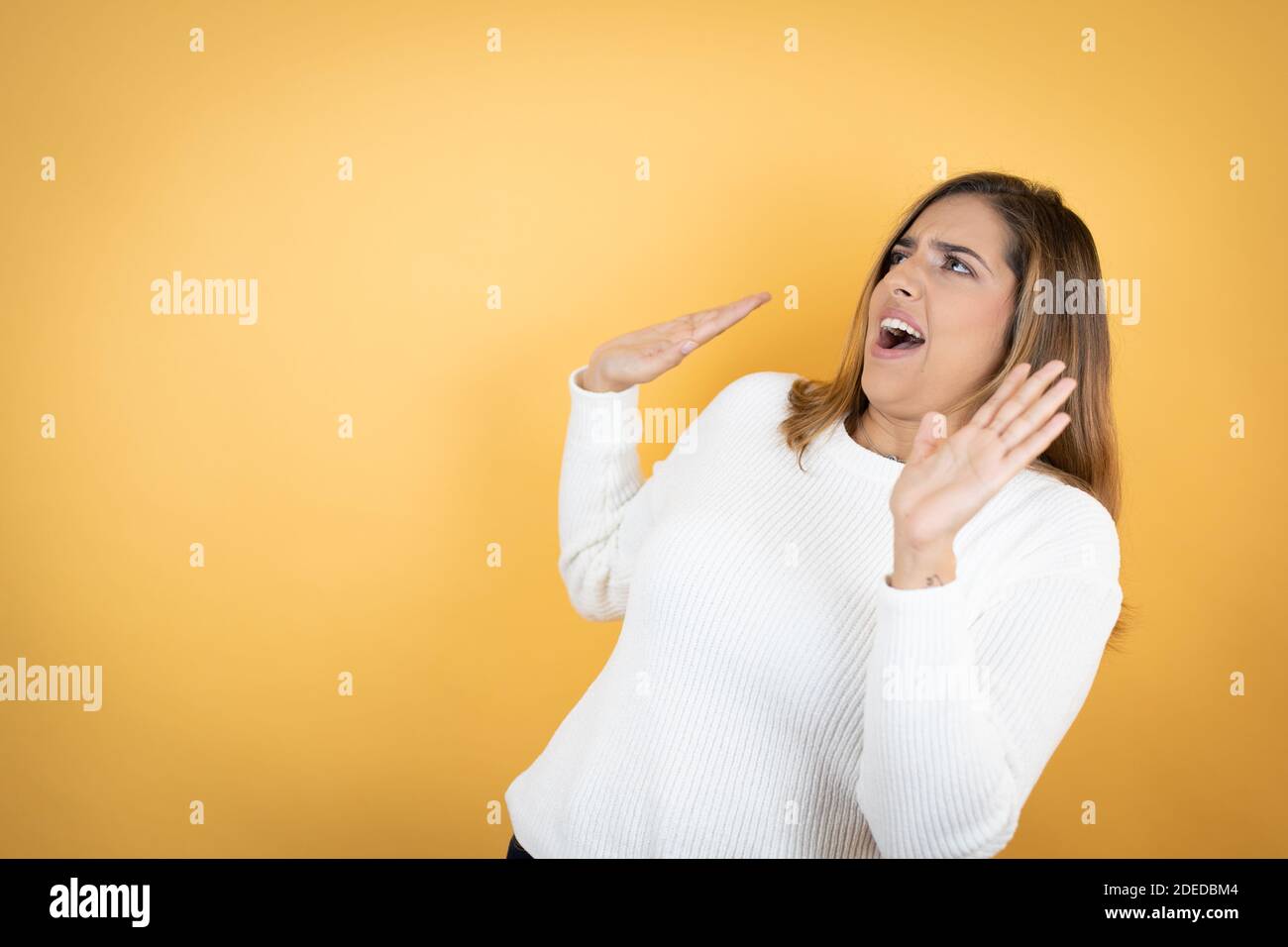 Young caucasian woman over isolated yellow background scared with her ...