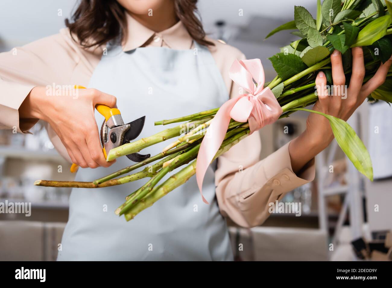 Cropped view of female florist with secateurs cutting stalks of tied ...