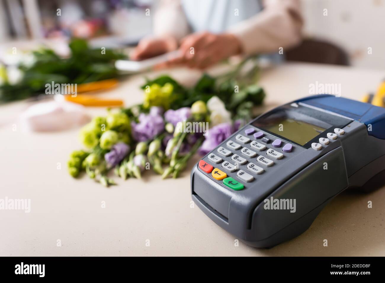 Close up view of terminal on desk with eustoma flowers near blurred ...