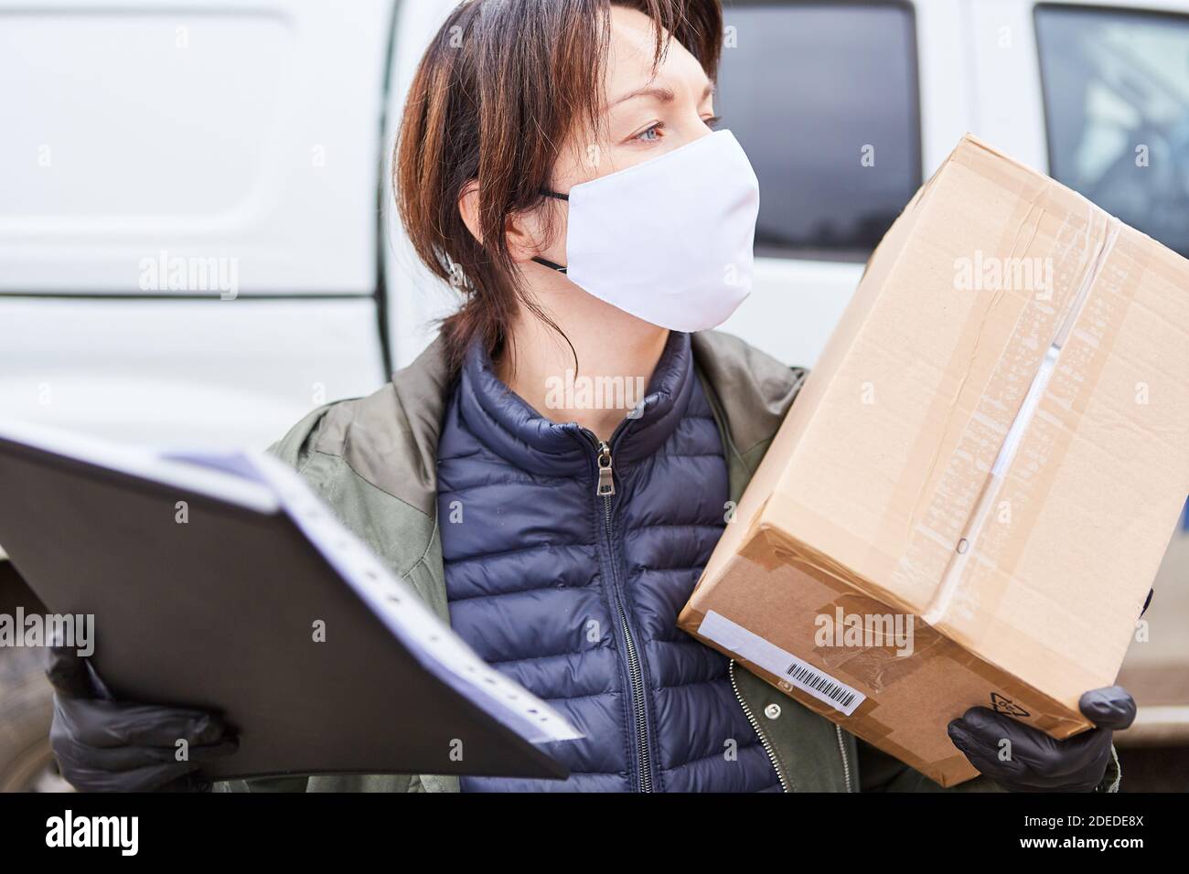 Delivery service parcel carrier with face mask delivers parcel and ...