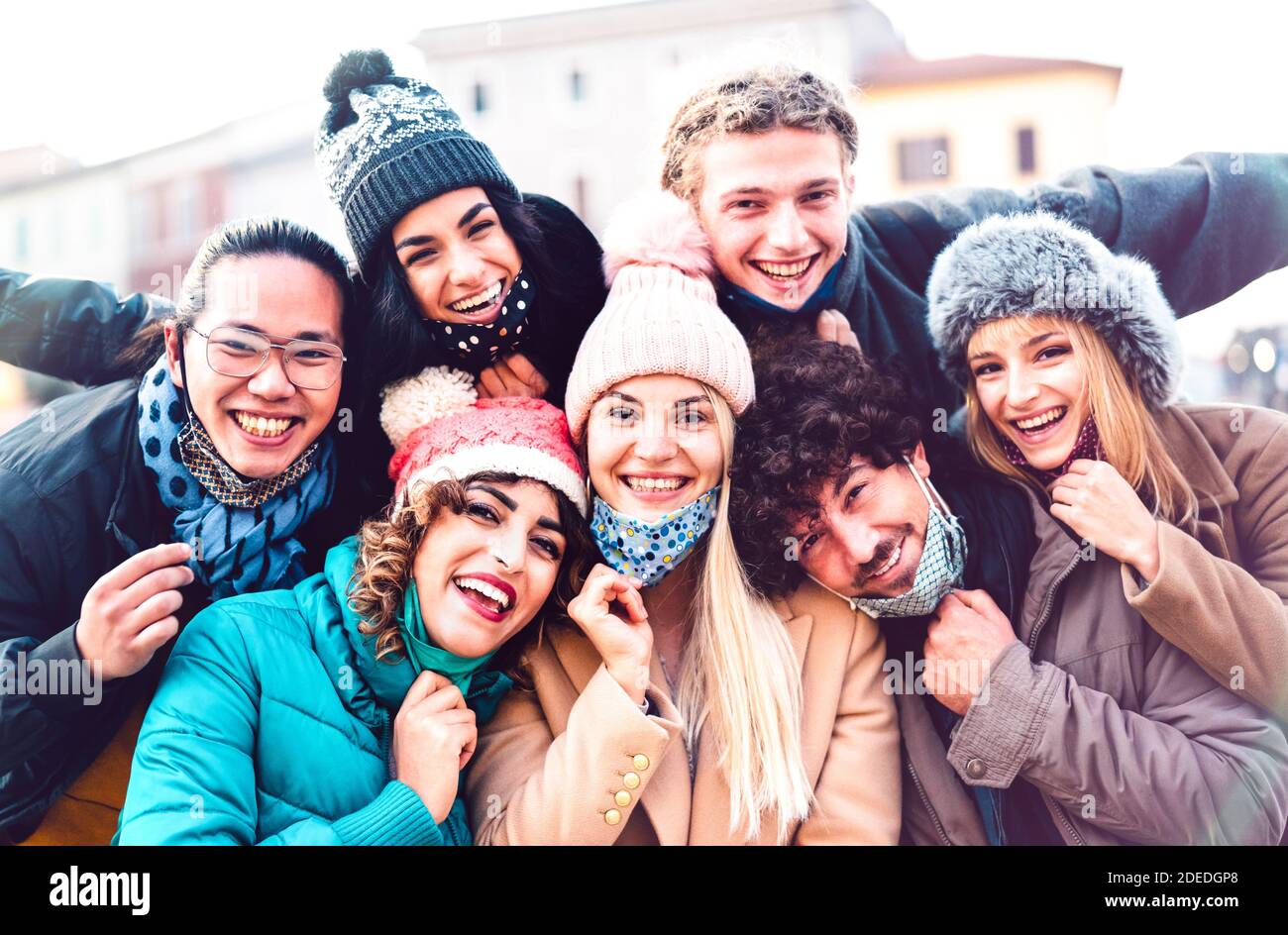 Multiracial friends taking selfie with open face mask and winter ...