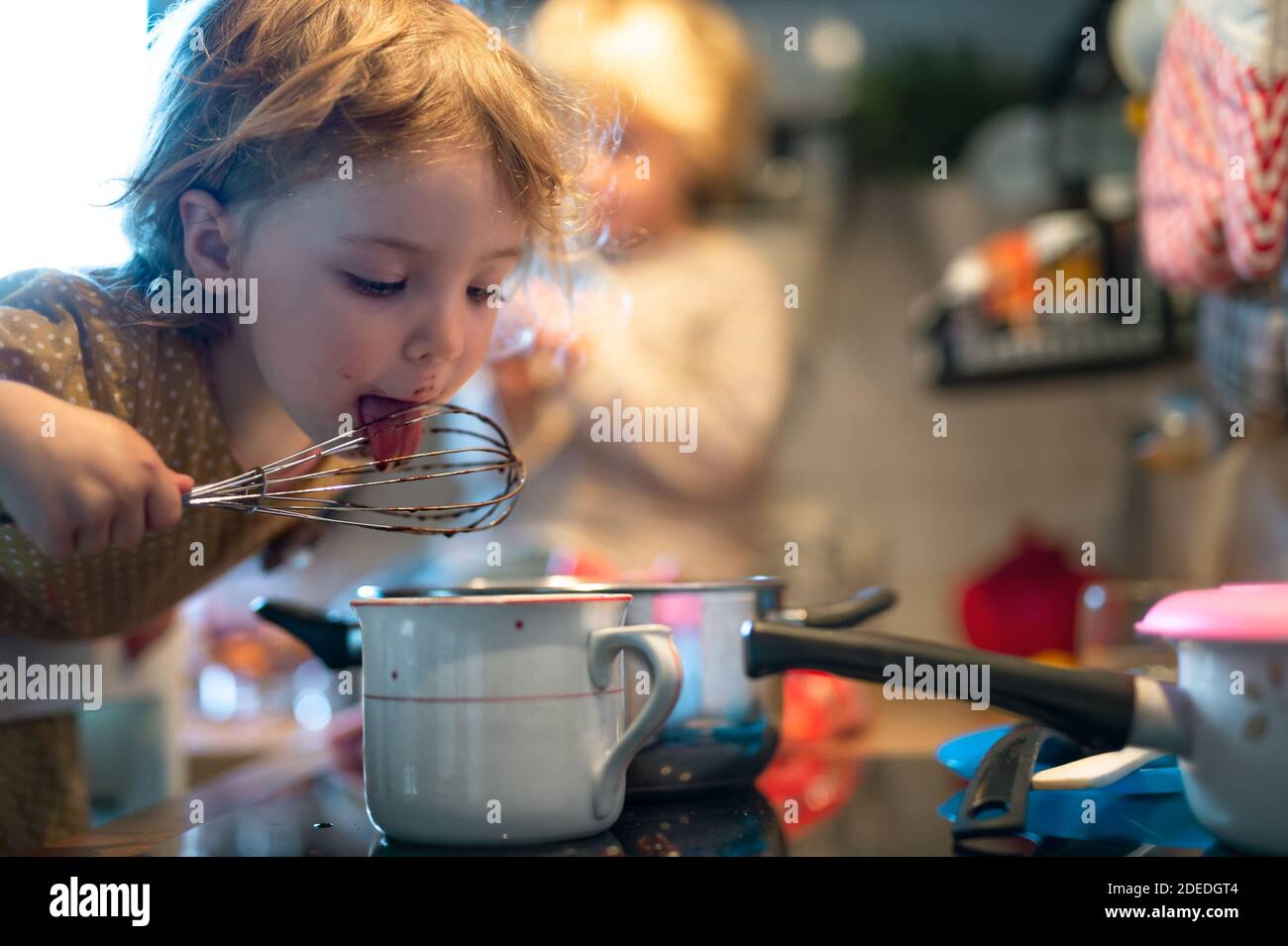 Small boy and girl indoors in kitchen at home, helping with cooking ...