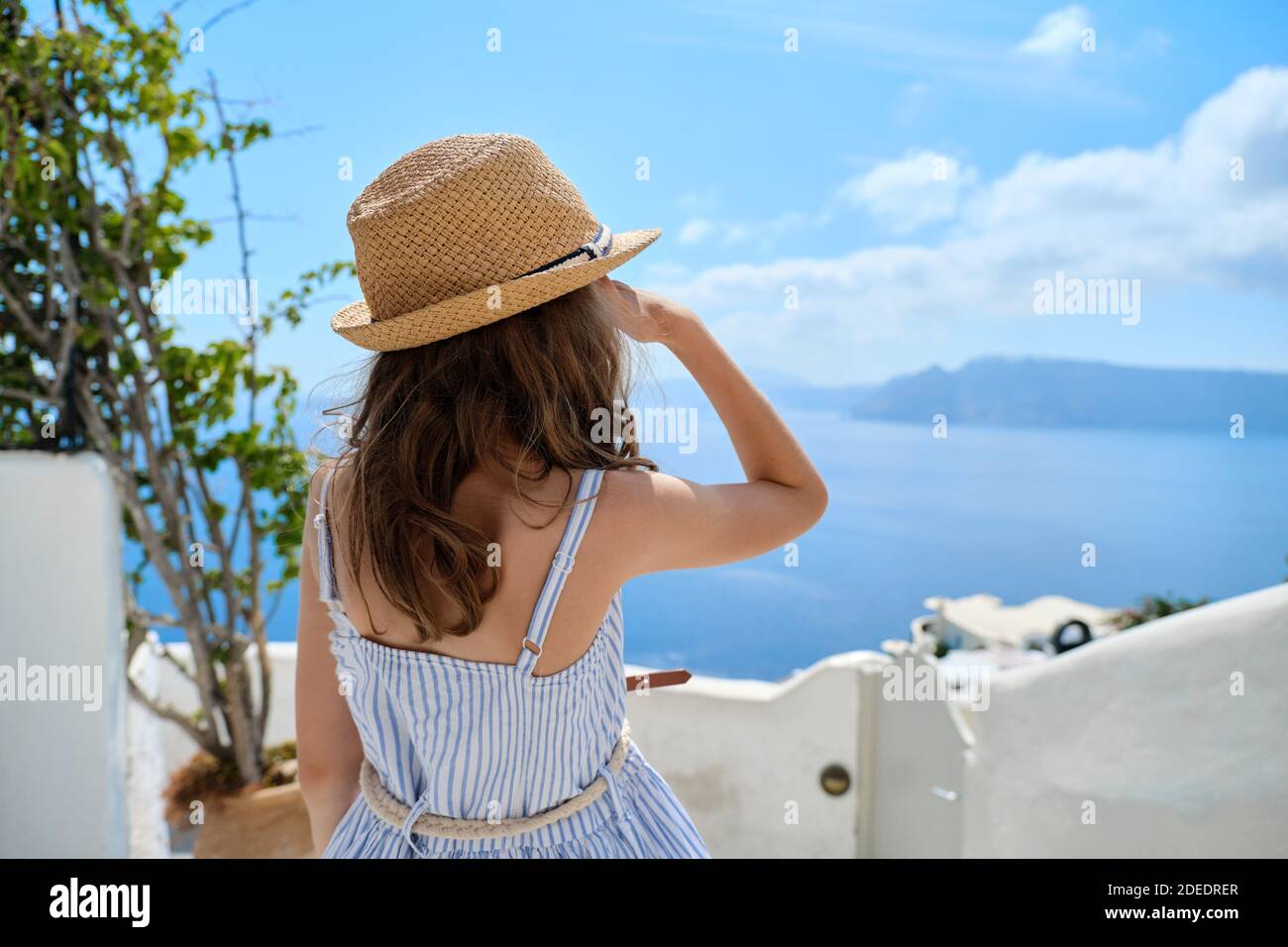 Famous Greek island Santorini, girl child in dress, hat back. Girl ...