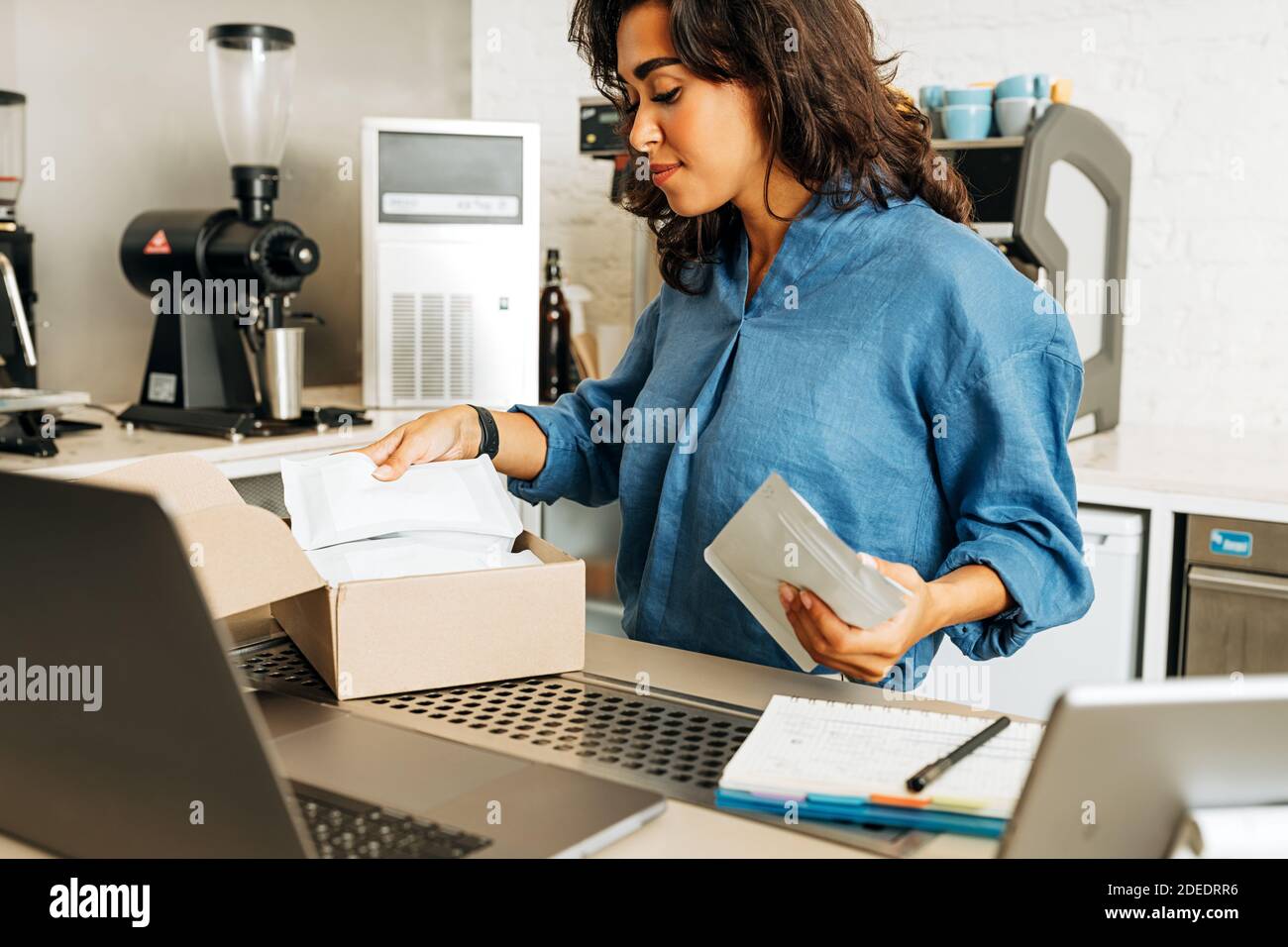 Cafe owner putting in a pack of coffee into a cardboard box Stock Photo ...