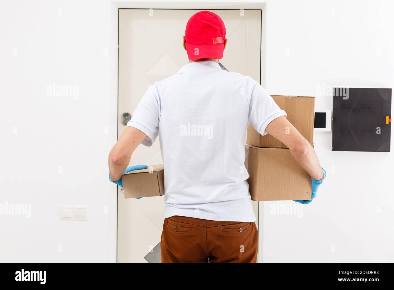 Delivery man in uniform with a big box view from behind Stock Photo - Alamy