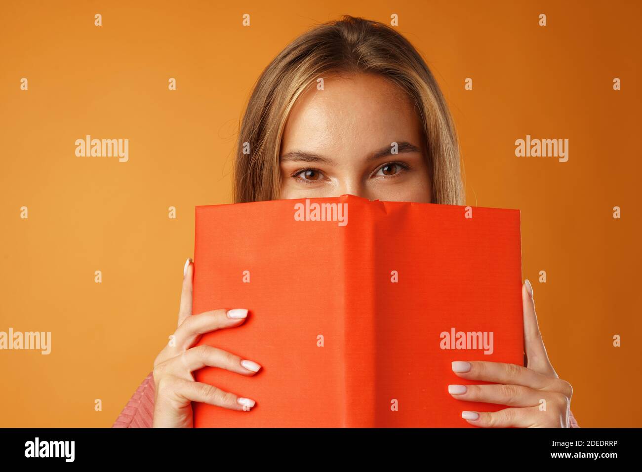 Beautiful young woman hiding behind the book Stock Photo - Alamy