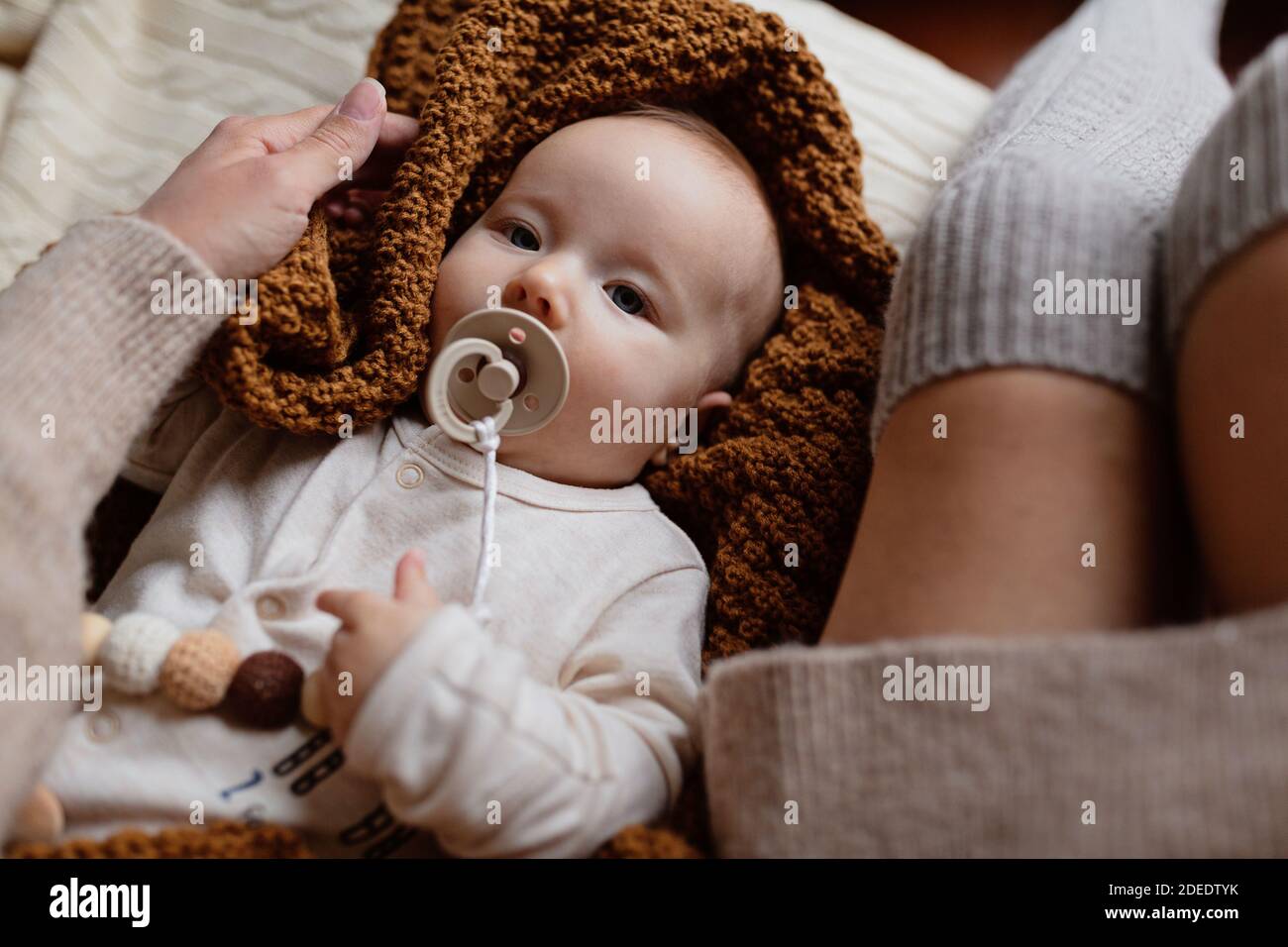 Cute caucasian baby girl lying on cozy bed with her mother dressed in ...
