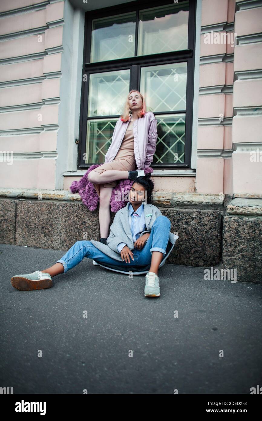 Two teenage girls infront of university building smiling, having fun ...