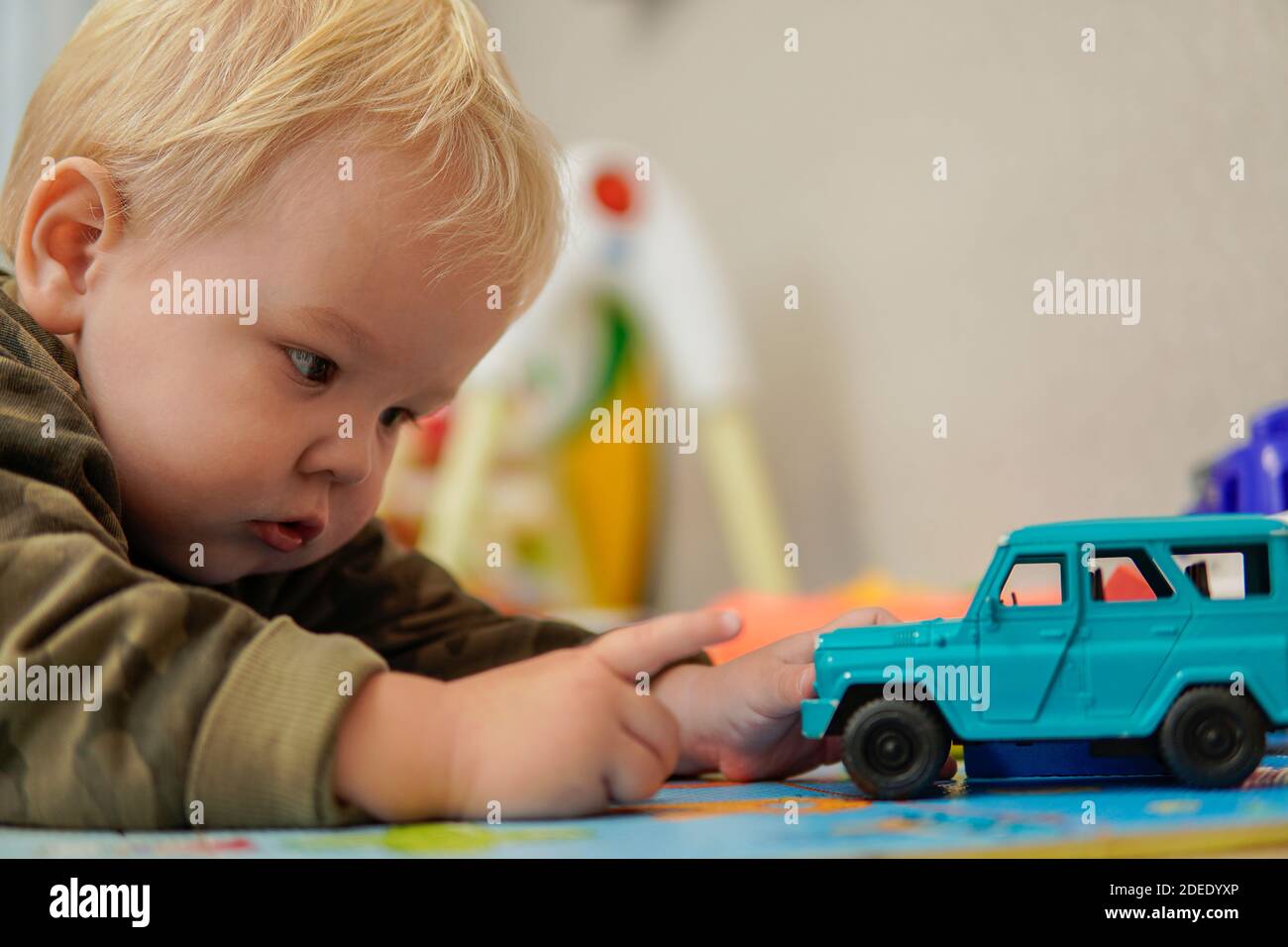 Little boy with blond hair playing with blue car. high quality Stock ...