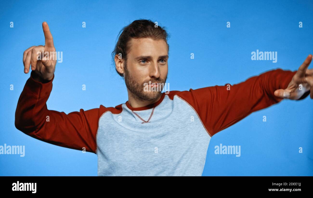 bearded young man pointing with fingers on blue Stock Photo - Alamy