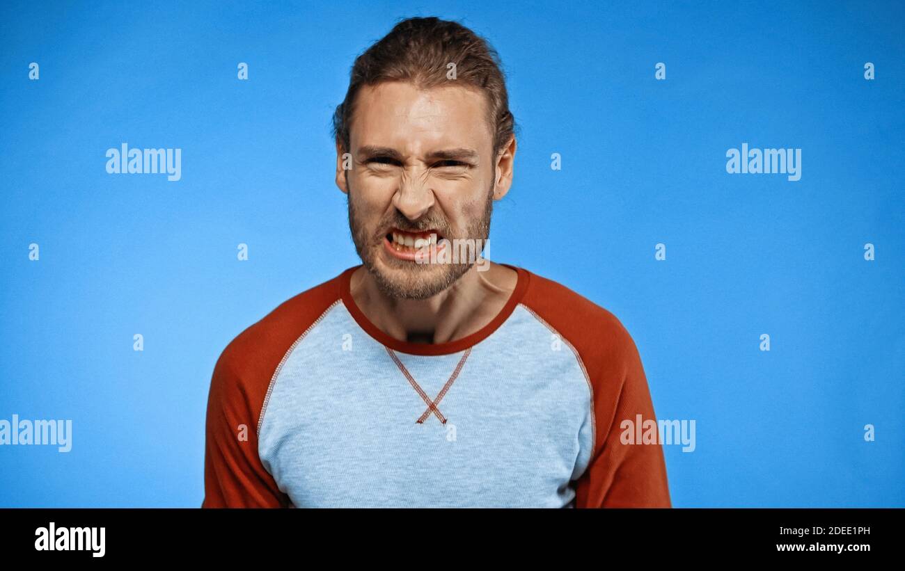 angry man looking at camera on blue background Stock Photo - Alamy