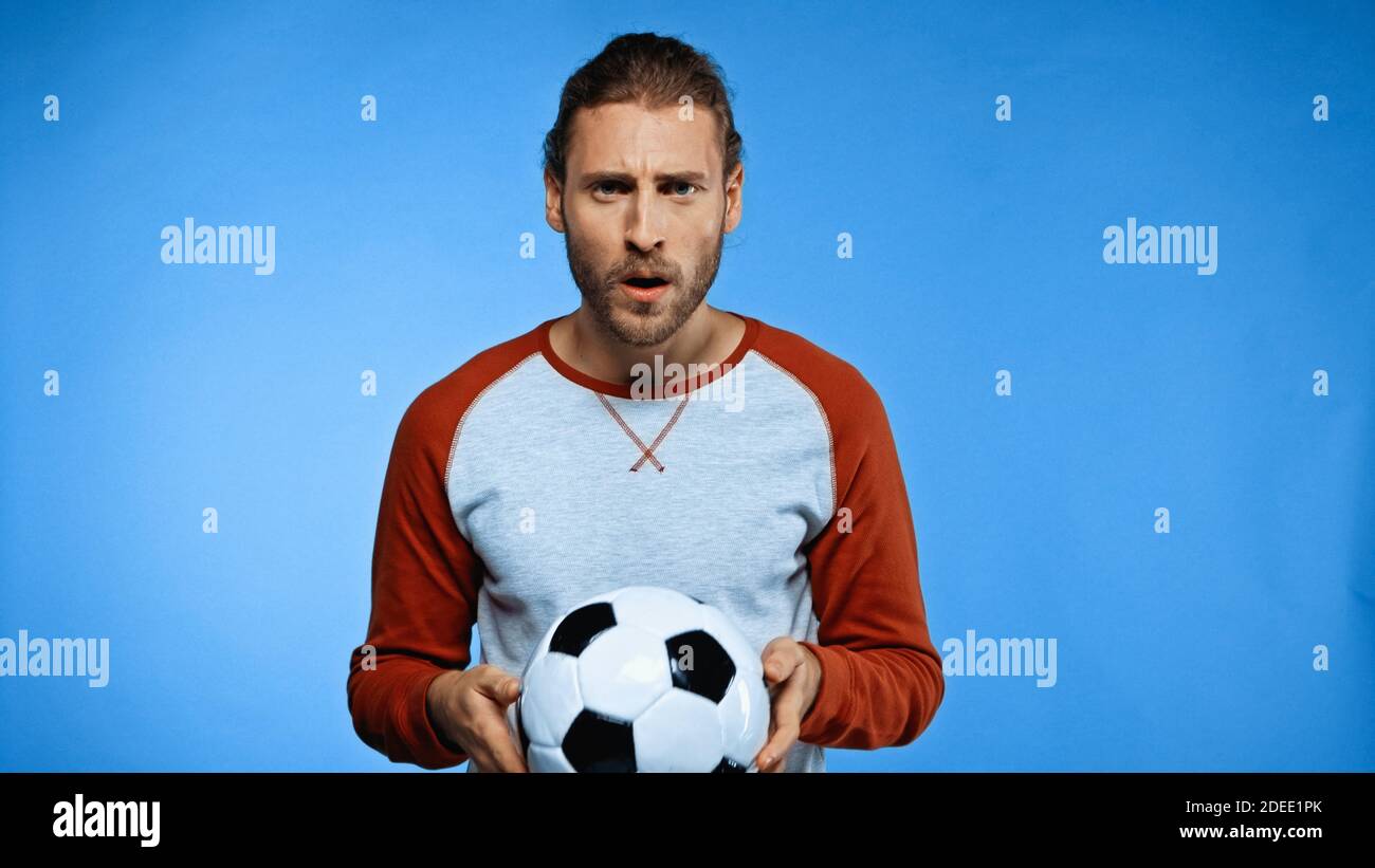 shocked football fan holding ball and screaming on blue Stock Photo - Alamy