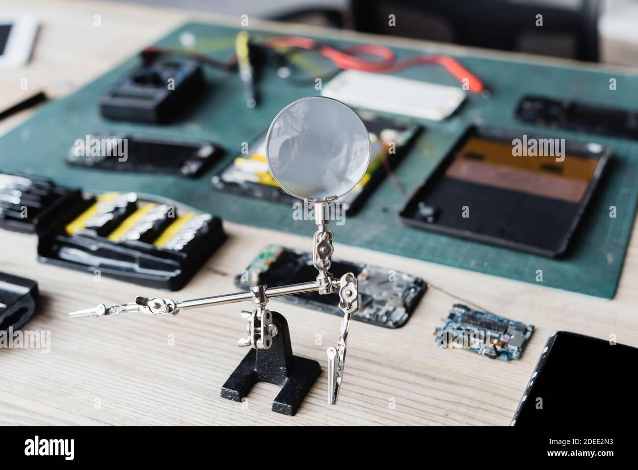 Flat lay of magnifier with disassembled parts of devices on workplace ...