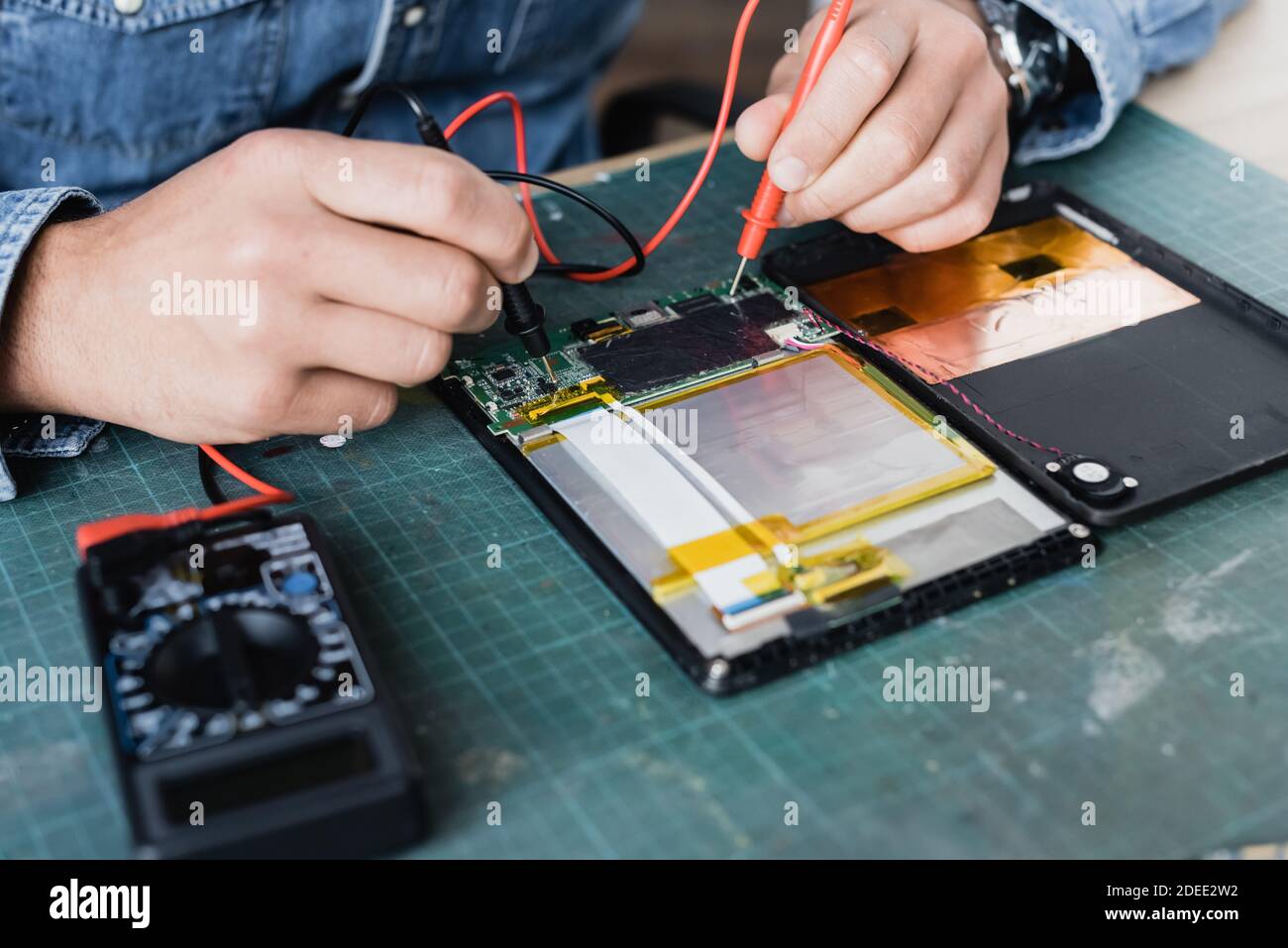 Close up view of repairman hands holding sensors of multimeter on part ...