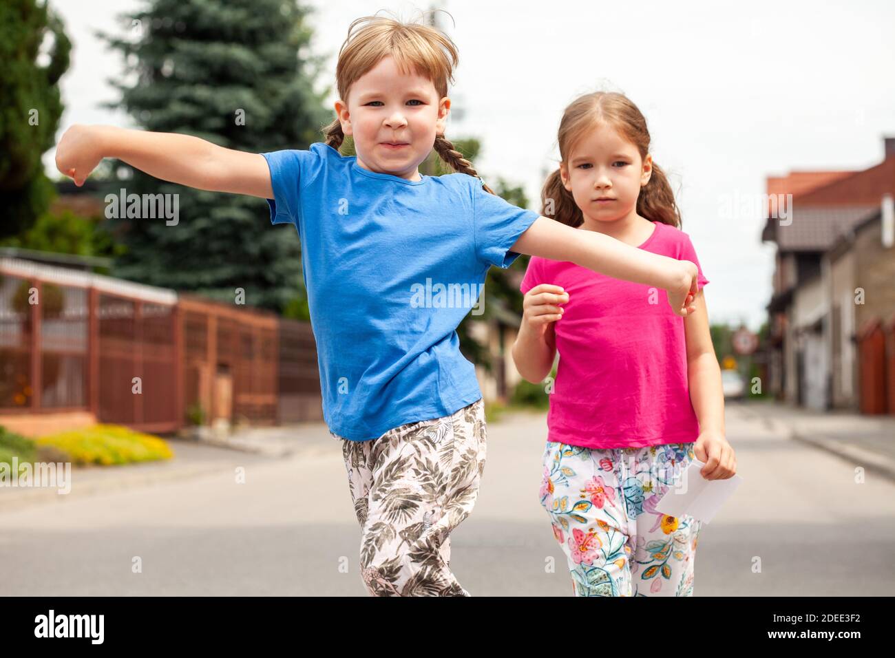 Two happy little children, sisters, siblings walking, girls jumping ...