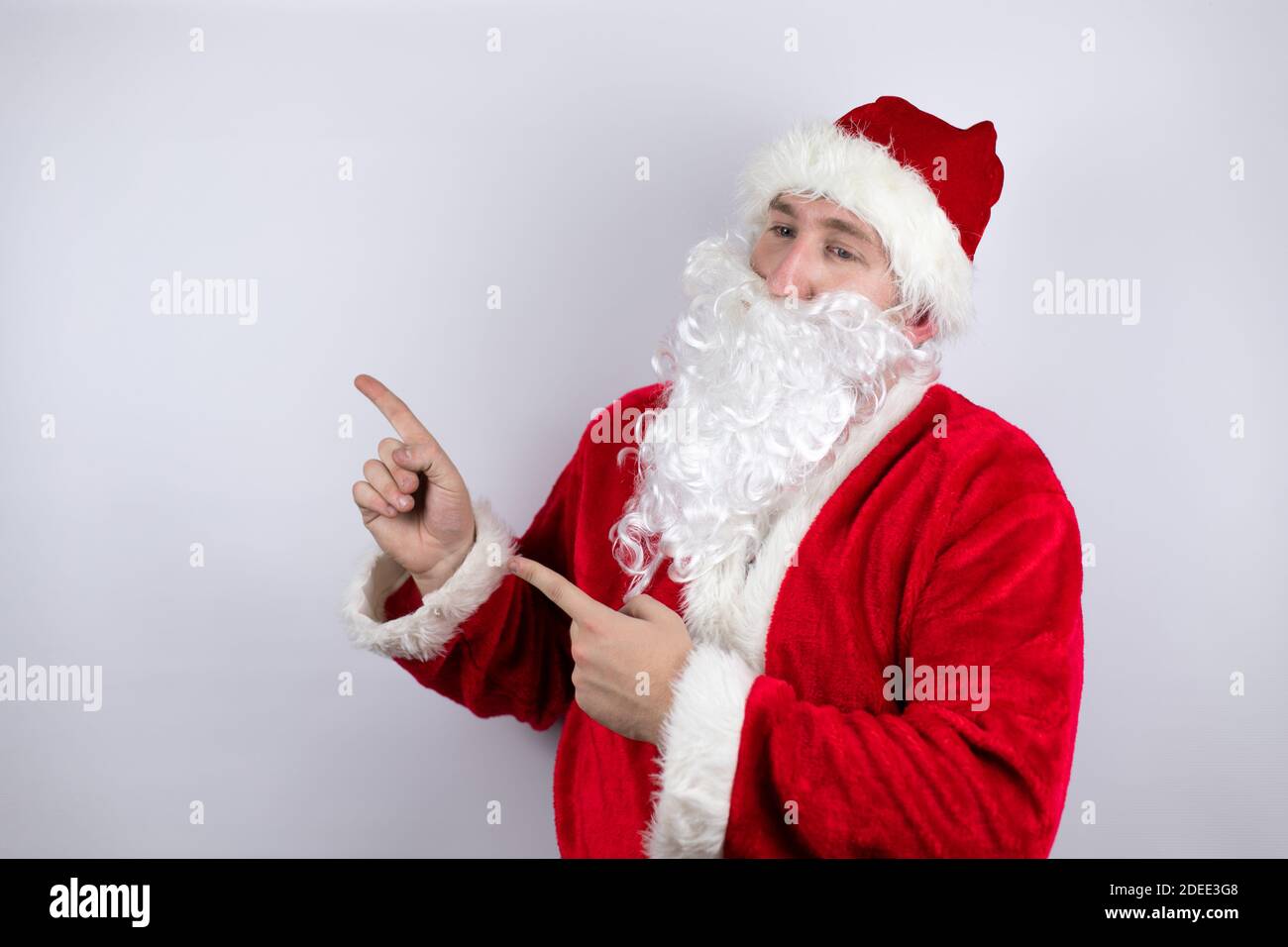 Man dressed as Santa Claus standing over isolated white background ...