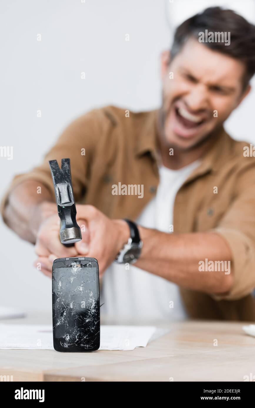 Aggressive businessman shouting while holding hammer near smashed ...