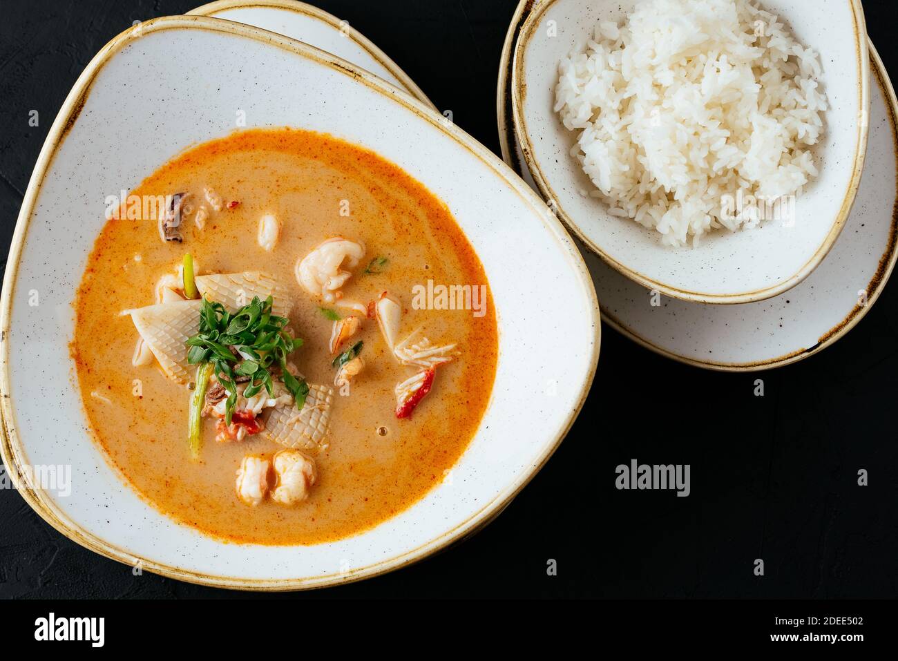 Asian Tom Yam soup with rice on a textured black background Stock Photo ...