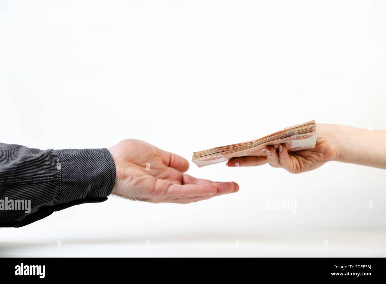 Bribery. A woman's hand gives a bribe a man's hand in a shirt. Side ...
