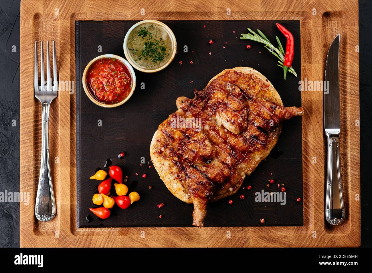 grilled whole chicken with vegetables and sauce on a black background ...