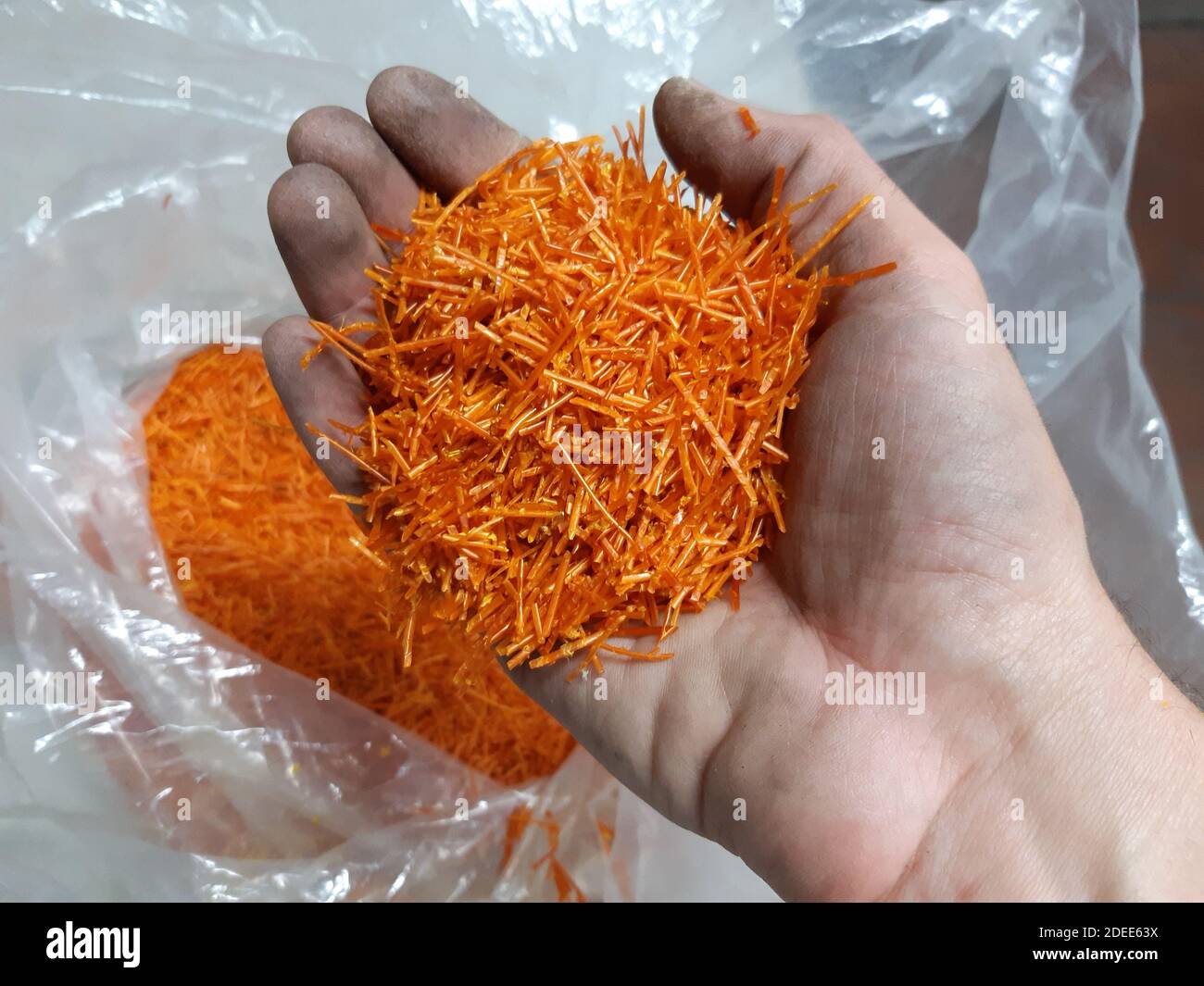 A closeup of a person holding orange plastic recycled pellets Stock ...