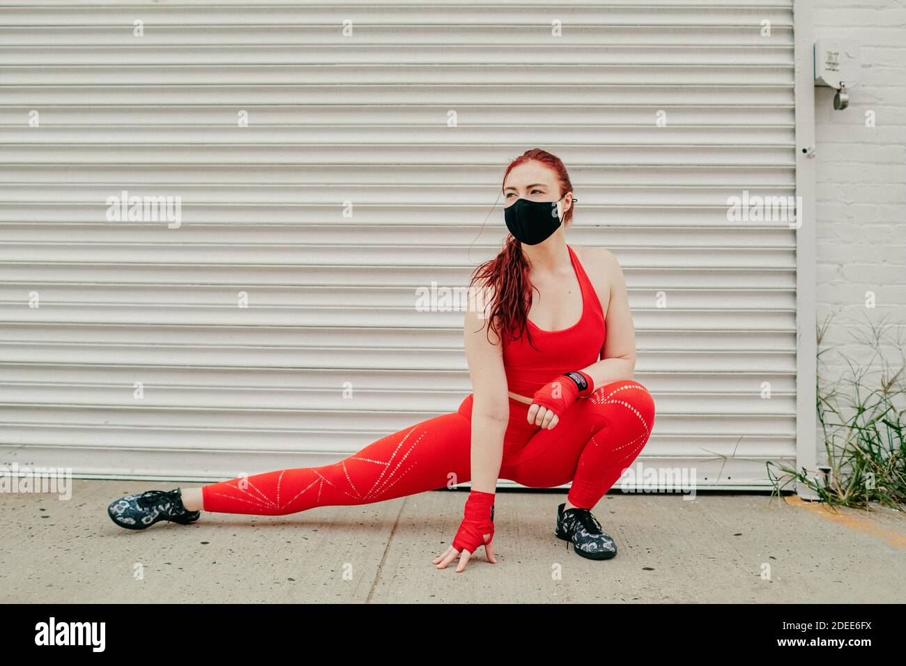 Young female boxer, stretching outdoors in Brooklyn wearing face-mask ...