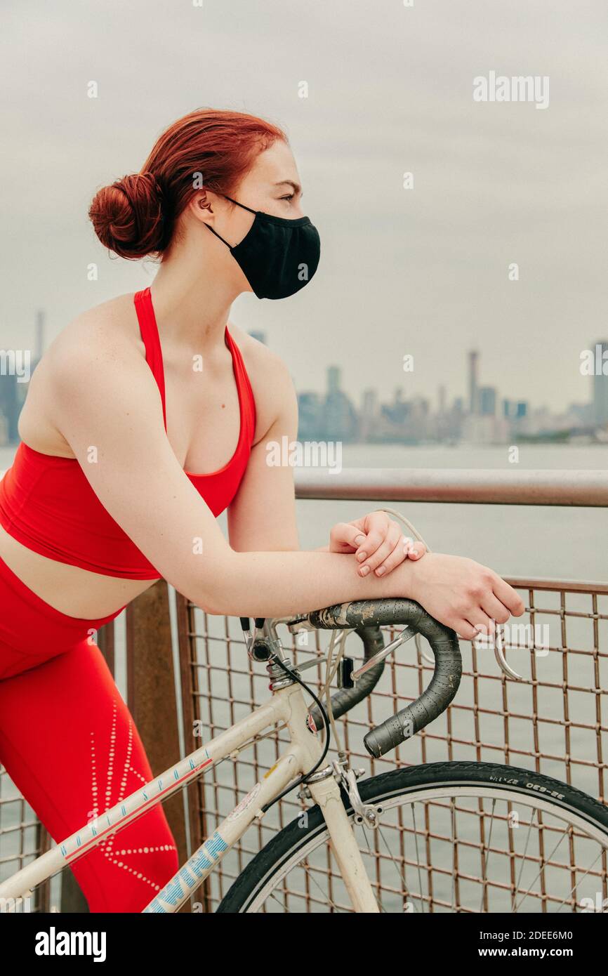 Young female cyclist wearing face mask with bike by waterfront Stock ...