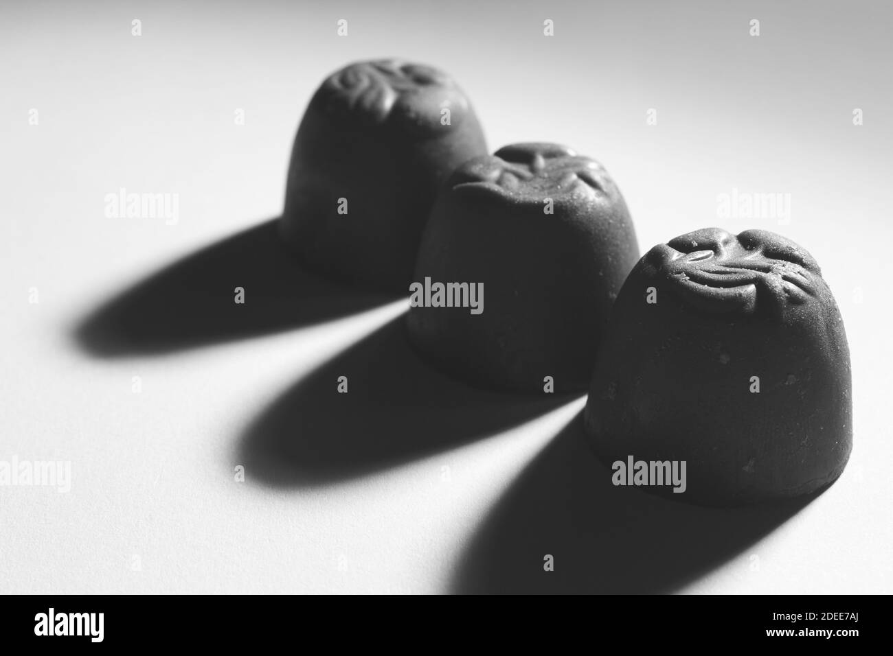 A grayscale shot of three chocolate candies and its shadow Stock Photo ...