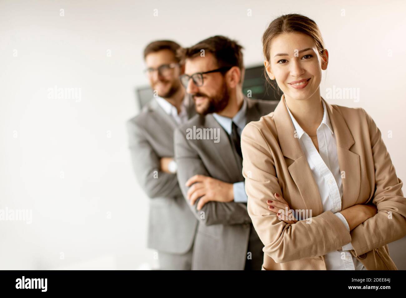 Smiling young business woman standing with group of corporate ...