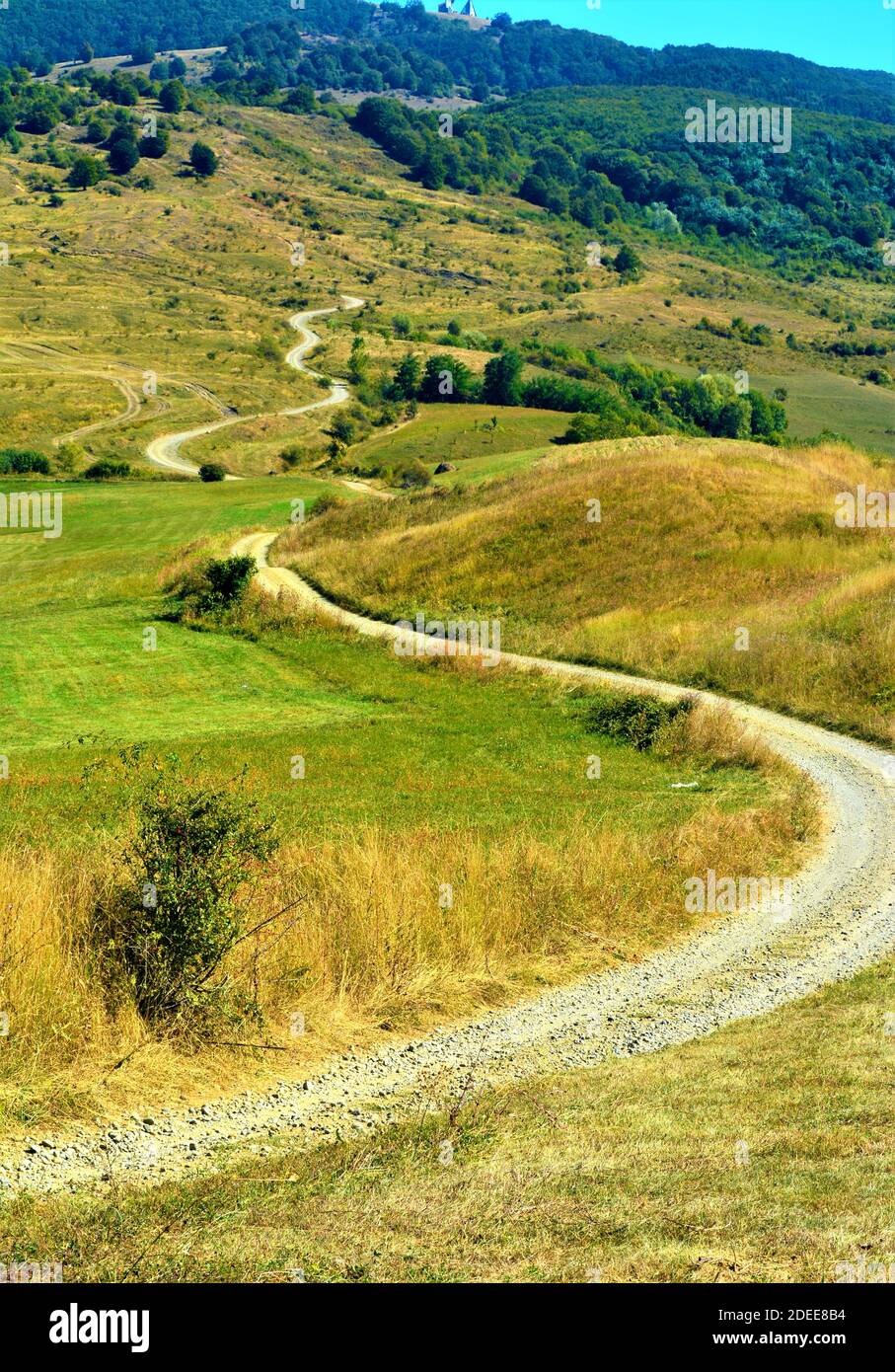 A scenic landscape view of a curved dirt road in the countryside Stock ...
