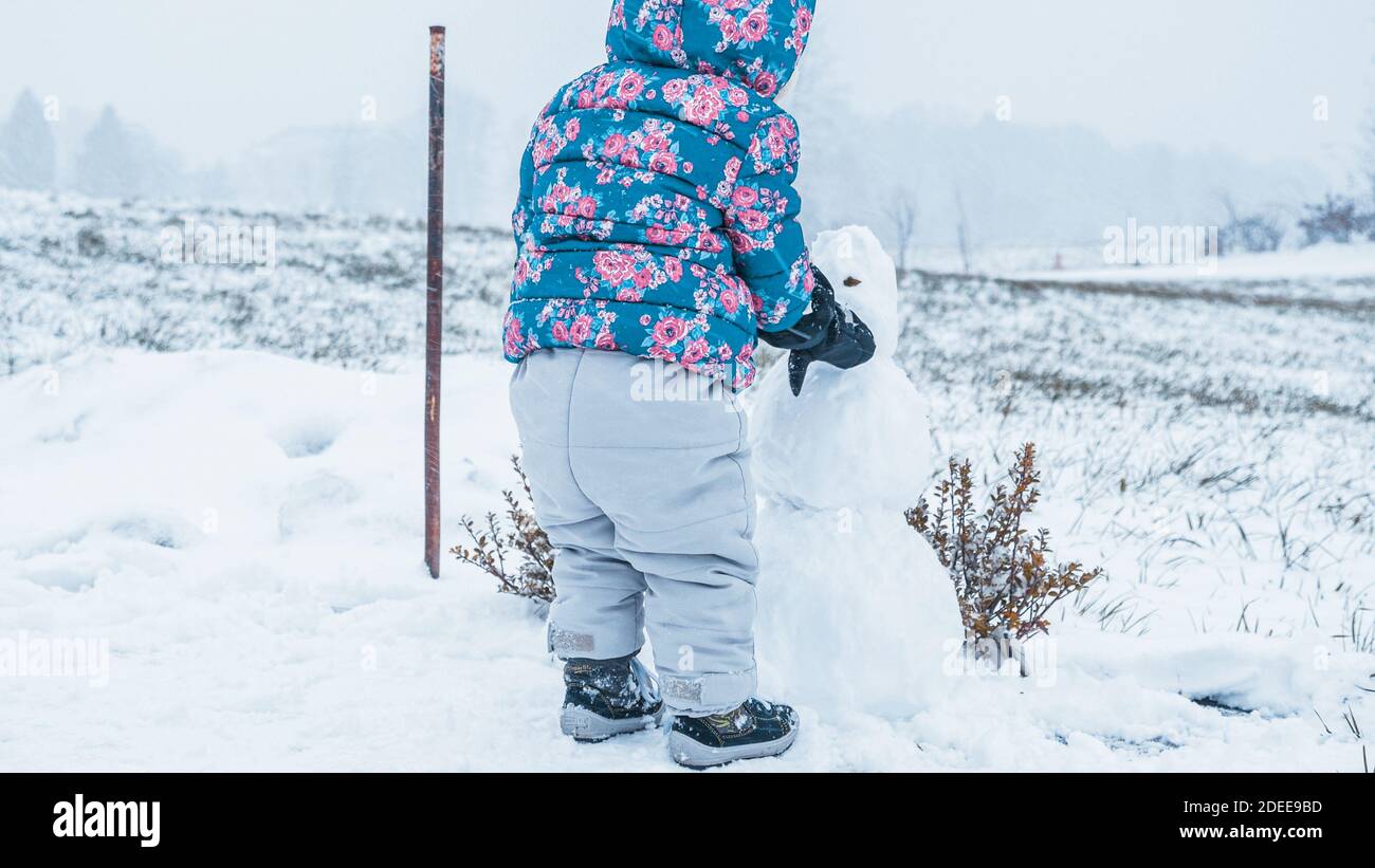 Child building snowman hi-res stock photography and images - Alamy