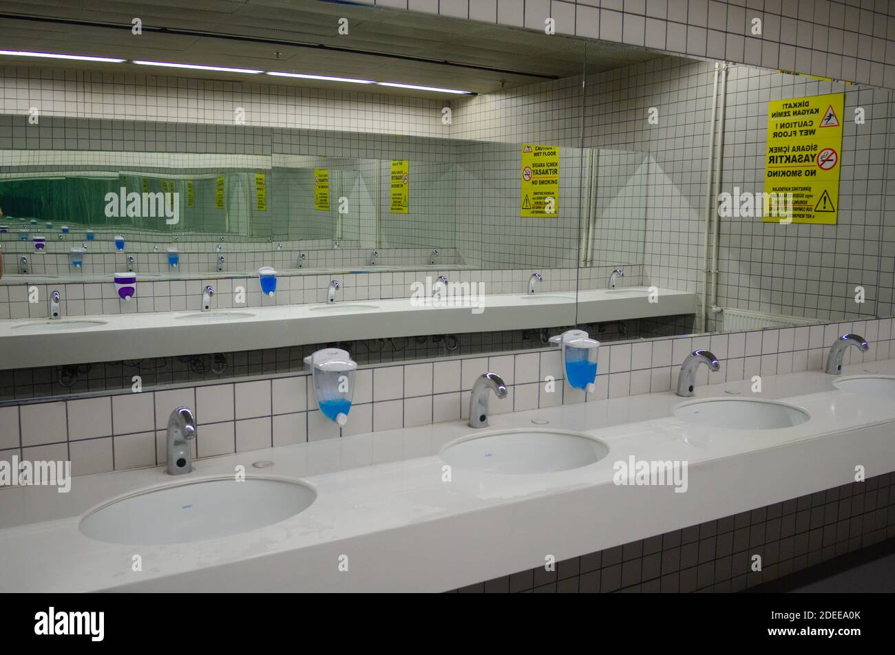 Empty public male restroom with mirror reflection with lavatory sinks ...
