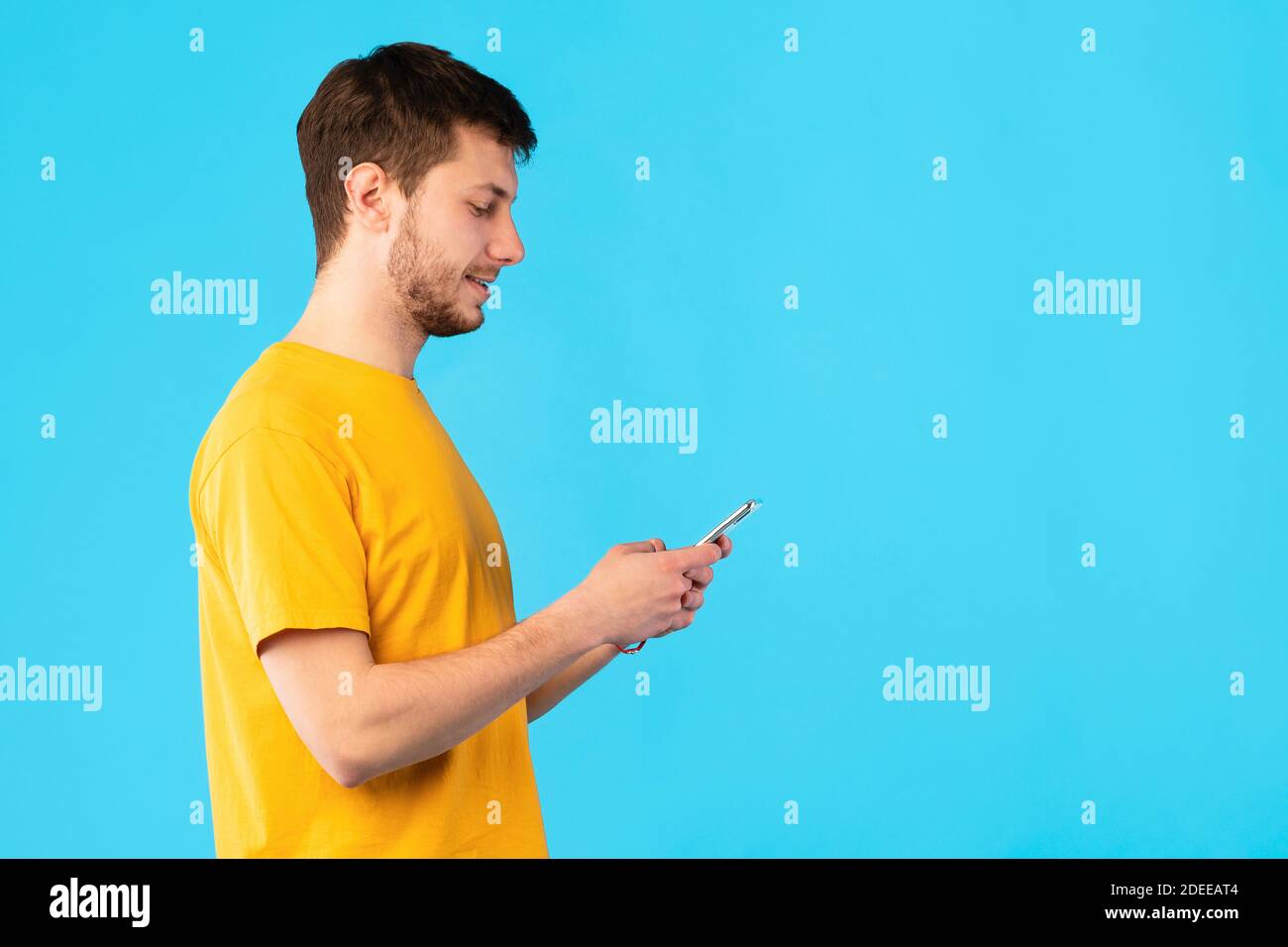 Portrait of young guy using mobile phone, side view Stock Photo - Alamy
