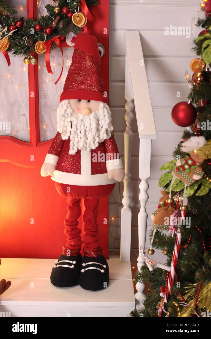 A figurine of red Santa Claus stands near a red door and a Christmas ...