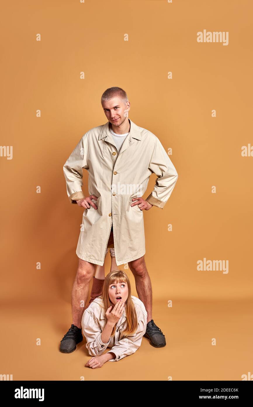 surprised blonde woman lie under the feet of man isolated, portrair of ...