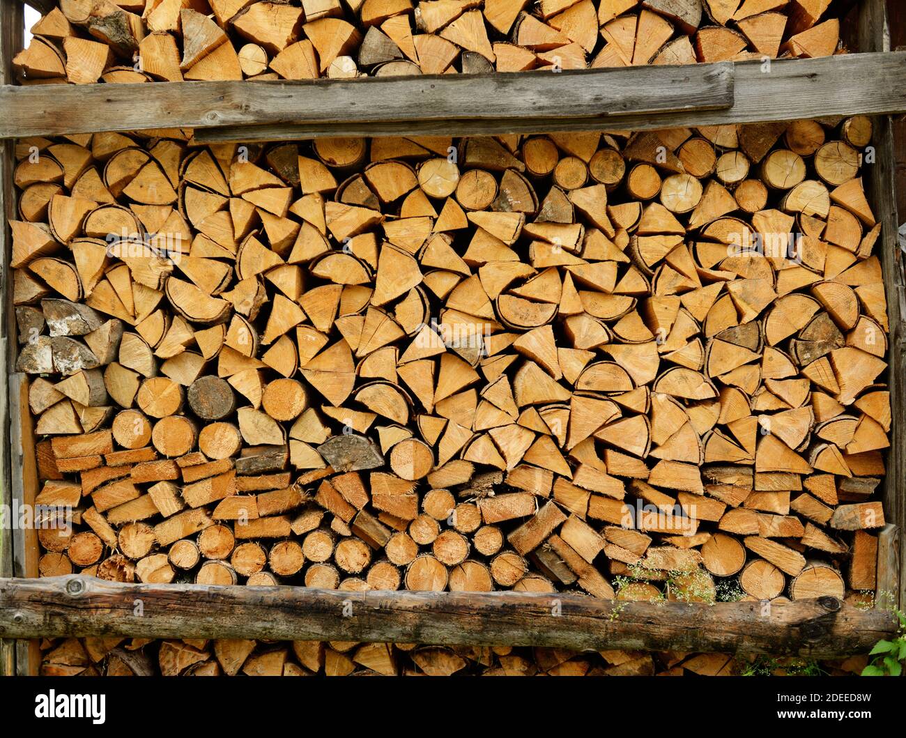Pile of small pieces of firewood in front of old wooden hut, stacked as ...