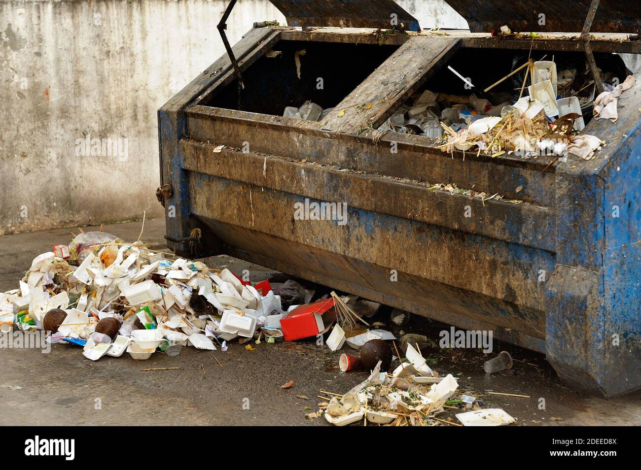 Pile of garbage outside full, disgusting, corroded trash container ...