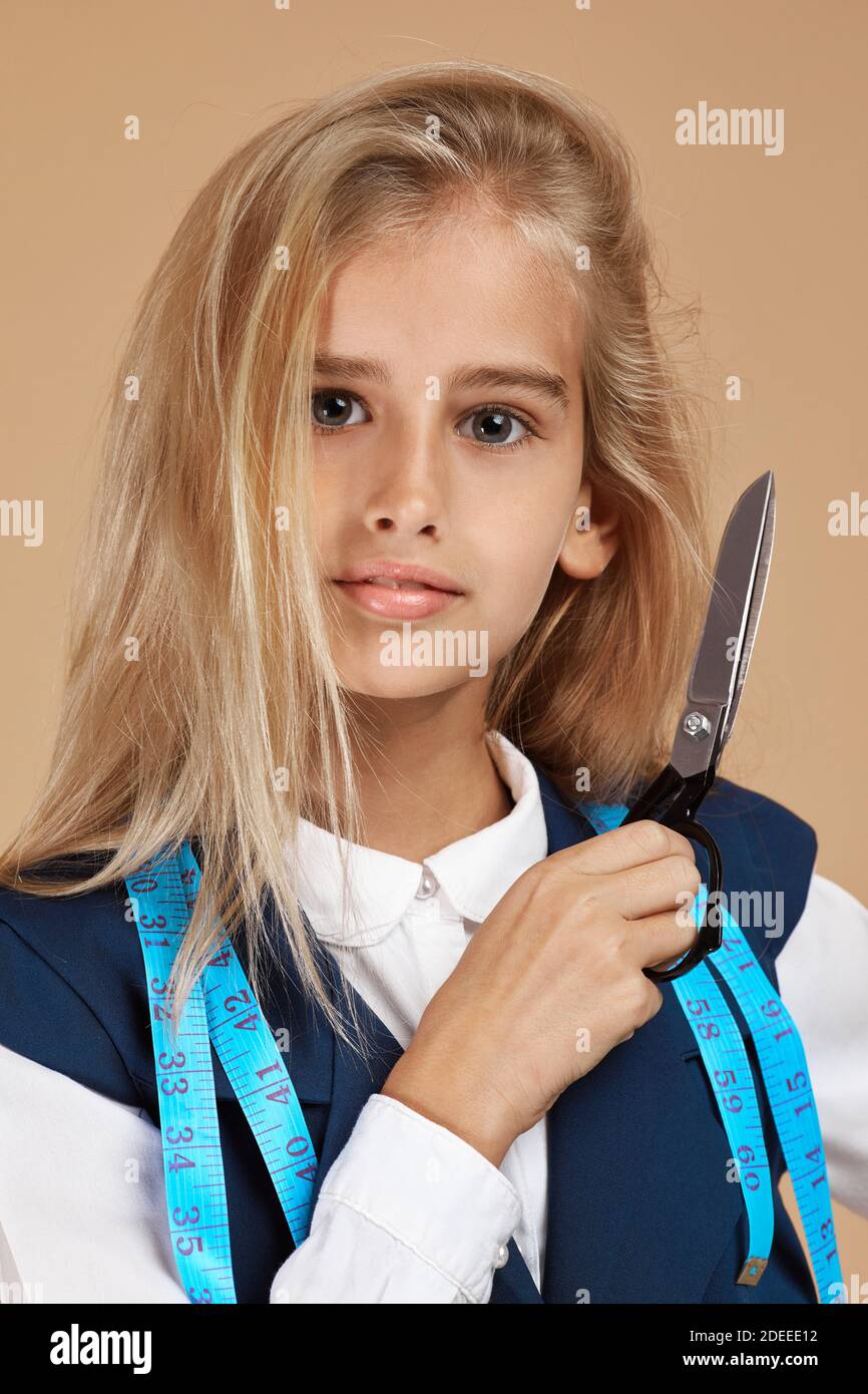 happy little girl with measuring tape and scissors on studio background ...