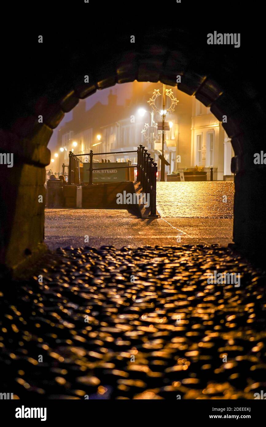 View through tunnel at night looking out to atmospheric UK street scene ...