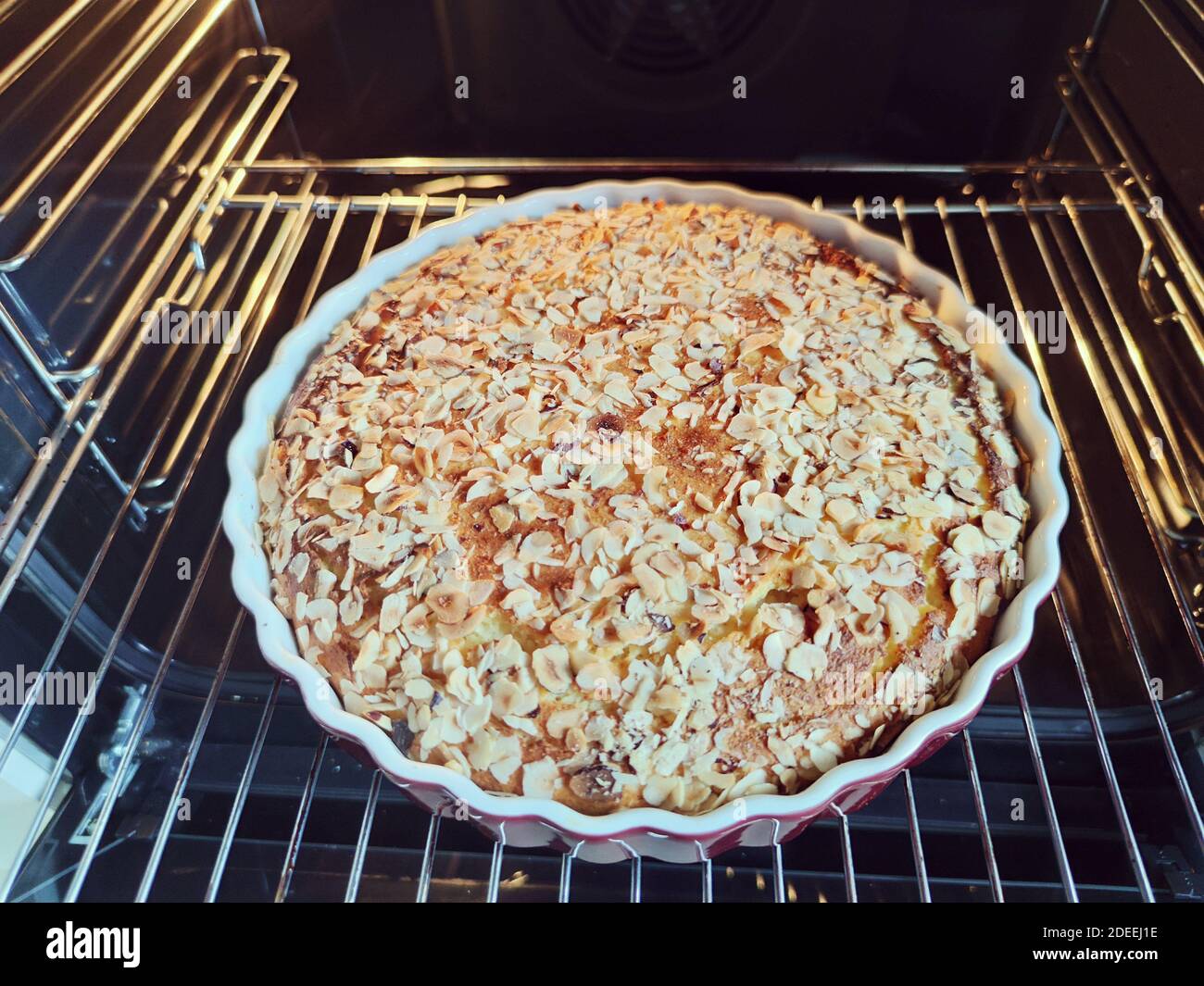 Fresh baked golden apple pie in red dish in hot oven at cozy kitchen ...
