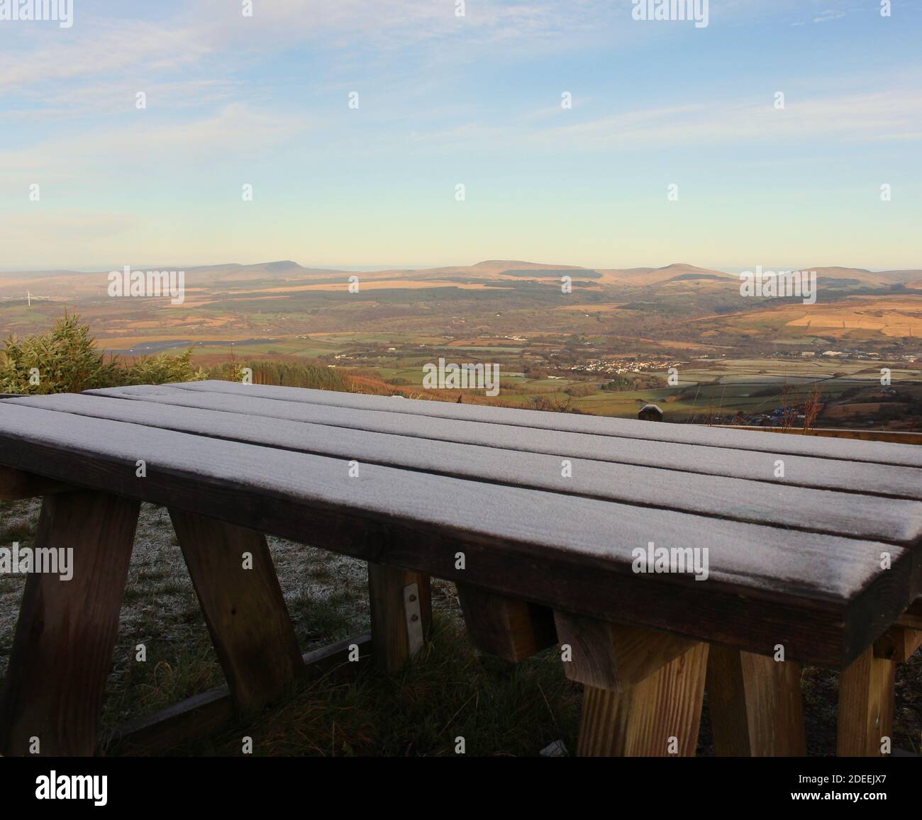 A photograph of a frosty wooden picnic bench atop a mountain viewpoint ...