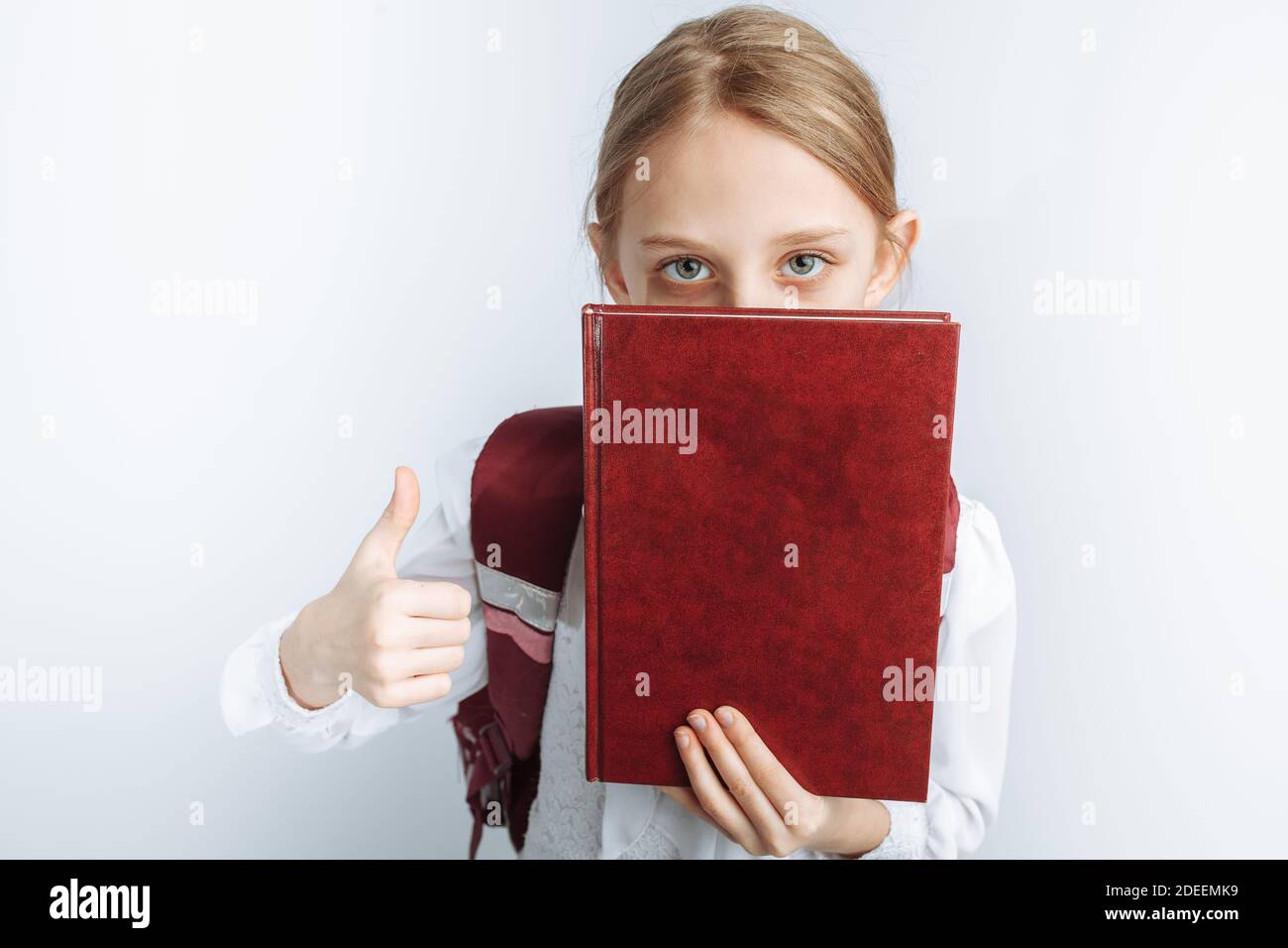 little cute girl is a schoolgirl, pointing at the book, white ...