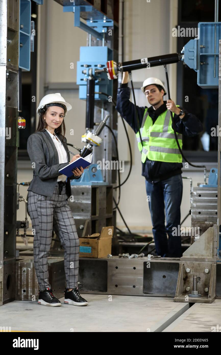 Portrait of a female factory manager in a white hard hat and business ...