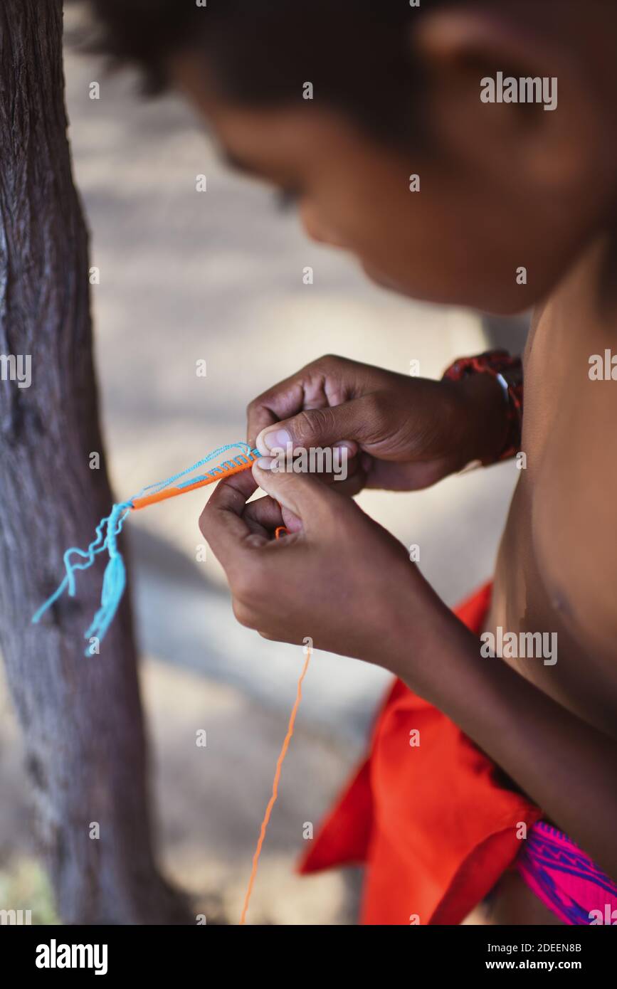 Wayuu indigenous kid hand making traditional thread bracelet, La ...