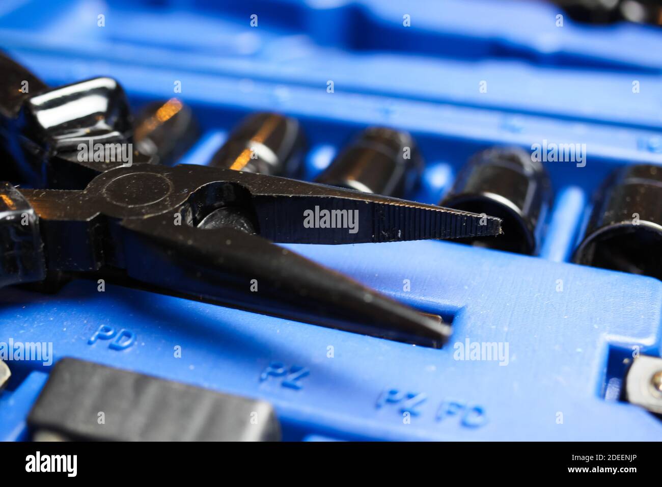 Macro close up of black isolated pliers on blue socket tool set box ...